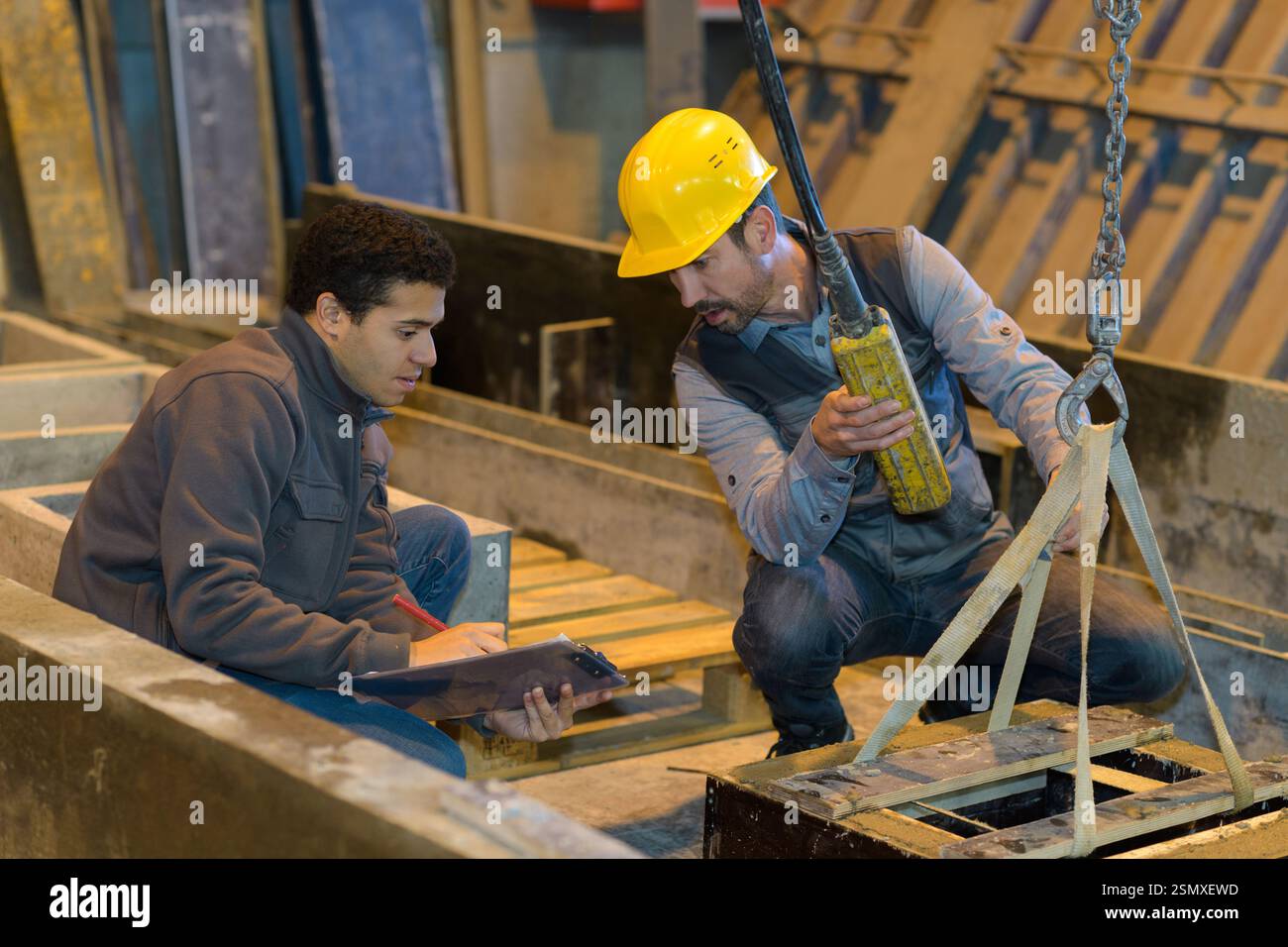 men using hoist in industrial building Stock Photo - Alamy