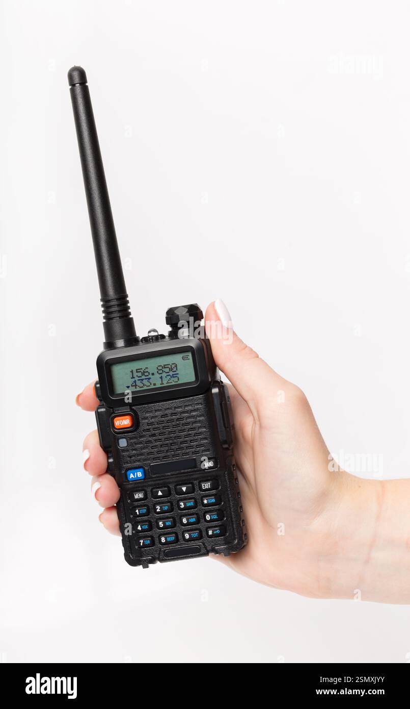 Handheld radio communicator held by a person with a visible display and ...