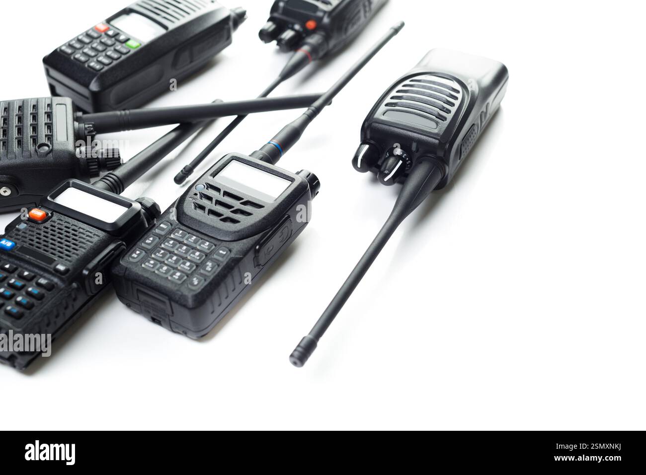 Communication devices arranged on a white surface with multiple two-way radios and antennas ...