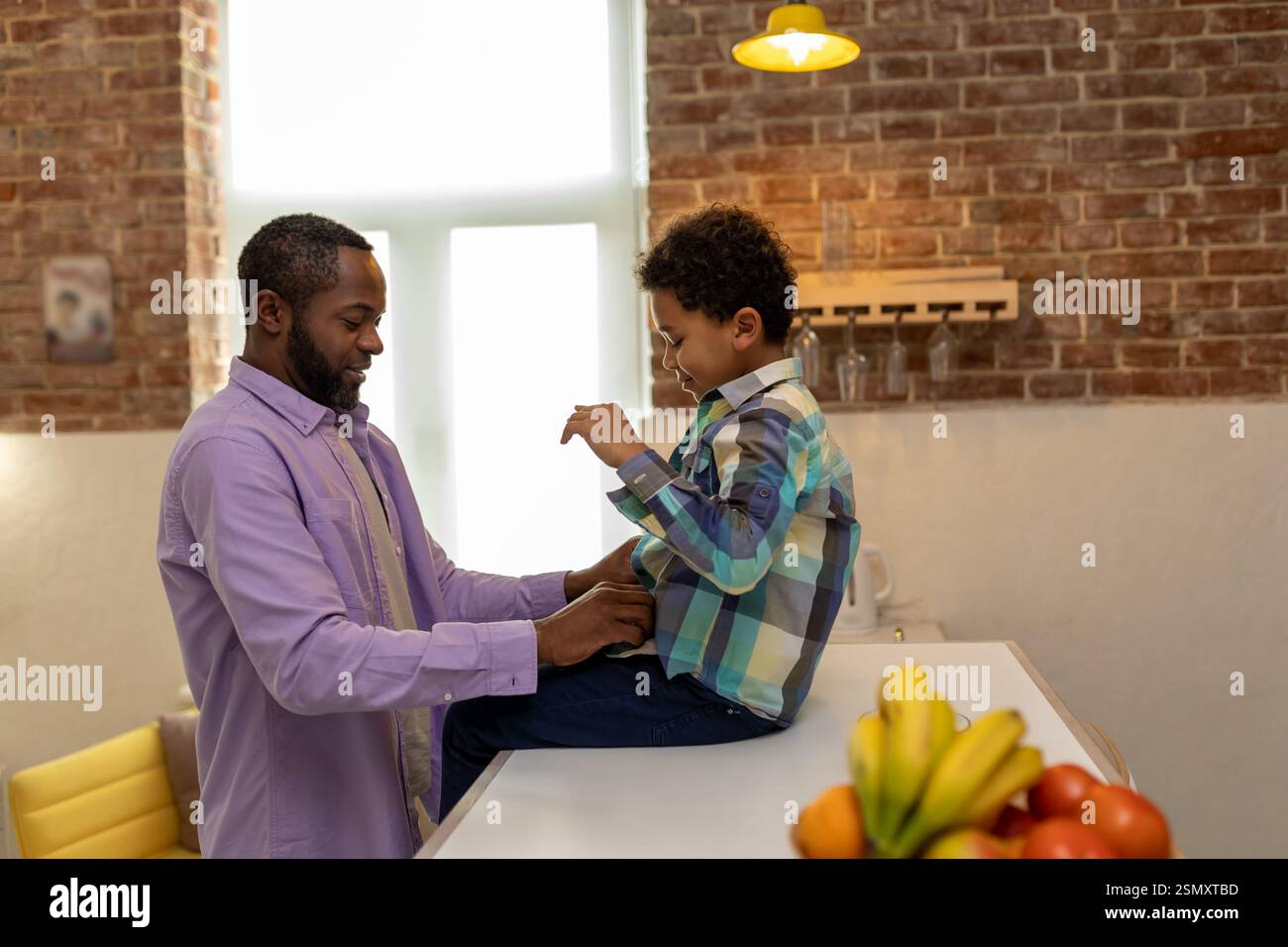 Father and son at home getting dressed in the kitchen and looking ...