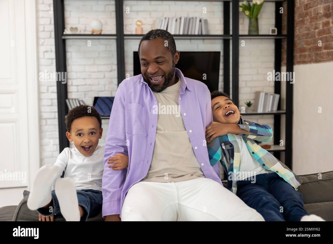 Happy dad sitting with his two sons and looking contented Stock Photo ...
