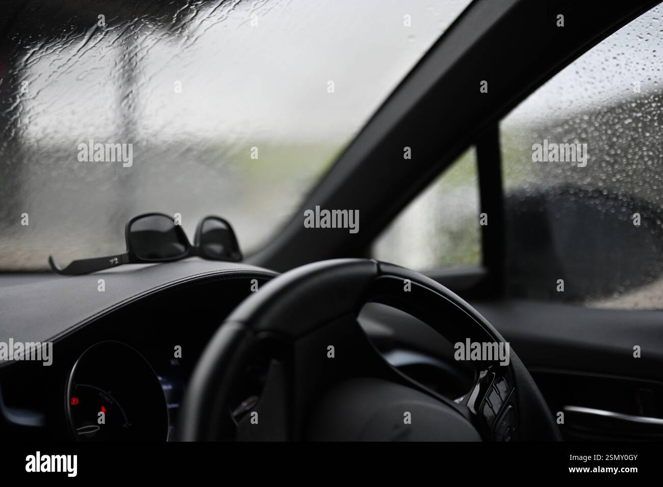 inside of car showing wet windscreen and steering wheel on a rainy day ...
