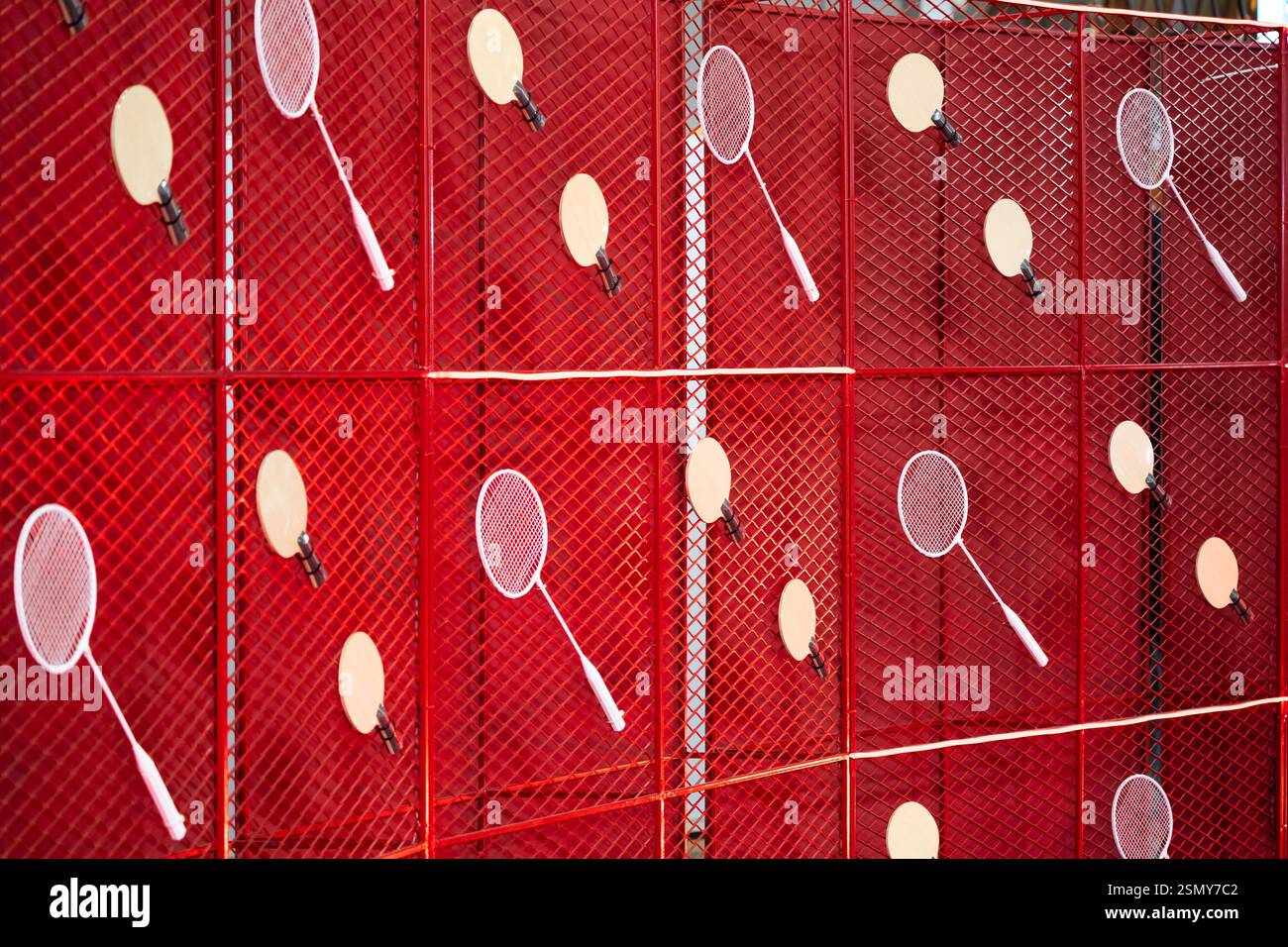 Table tennis and badminton rackets are hung on a red square grill steel ...
