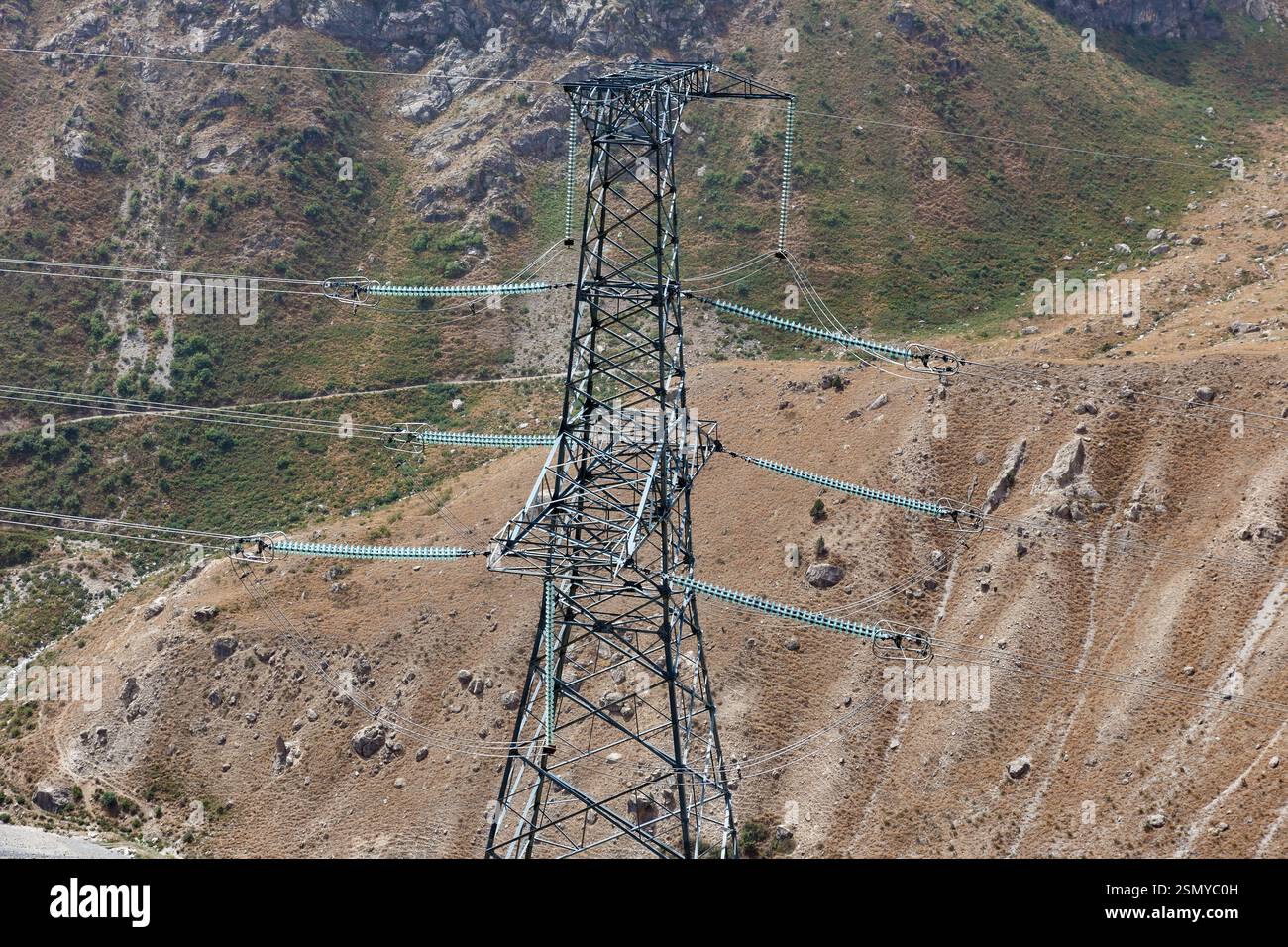 A tall electricity transmission tower towers above the mountainous ...