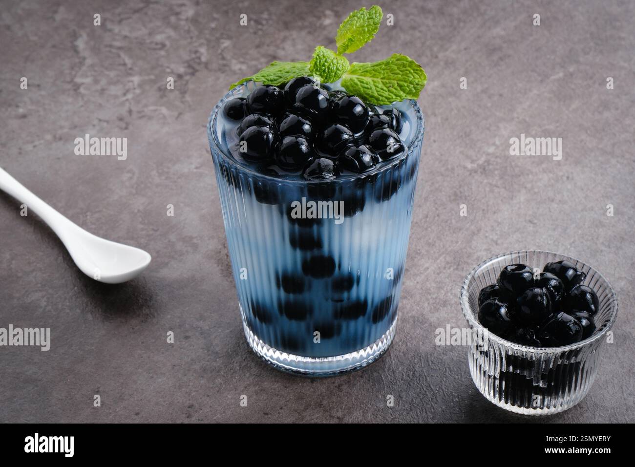 Butterfly pea milk bubble tea with boba tapioca pearls and mint garnish ...