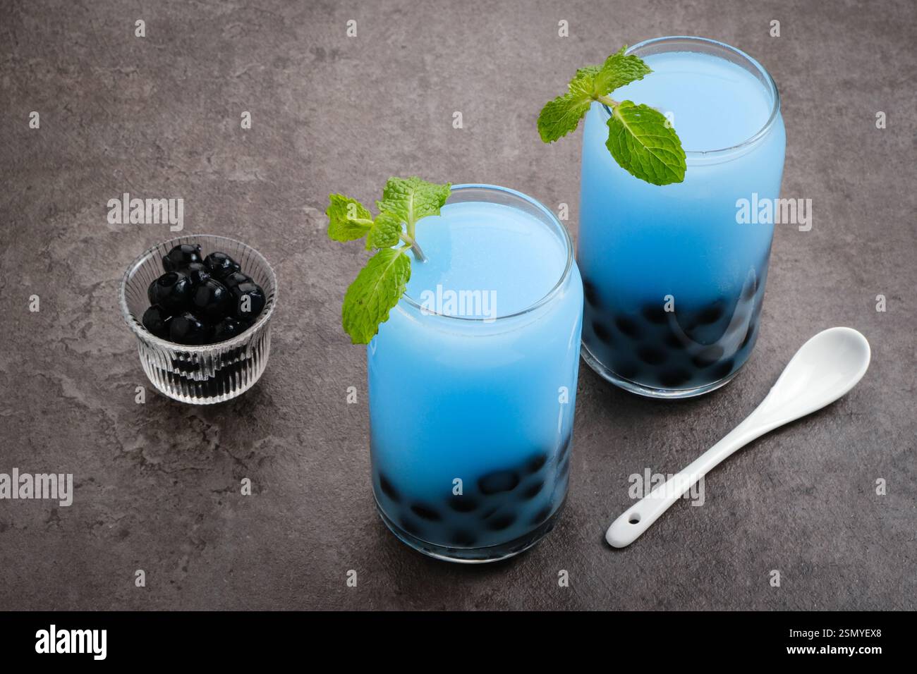 Butterfly pea milk bubble tea with boba tapioca pearls and mint garnish ...