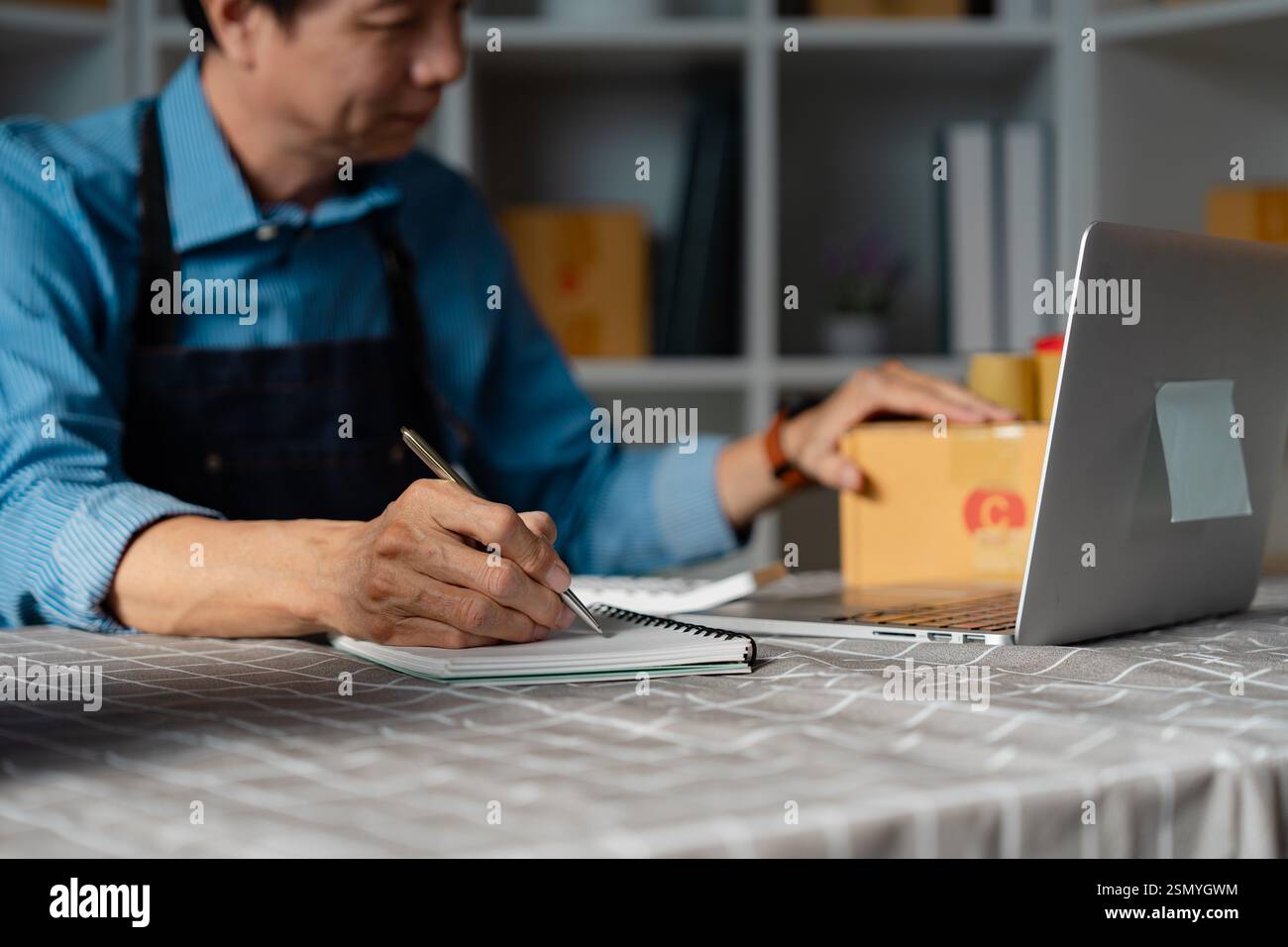 Business owner taking notes while managing inventory and orders with a ...