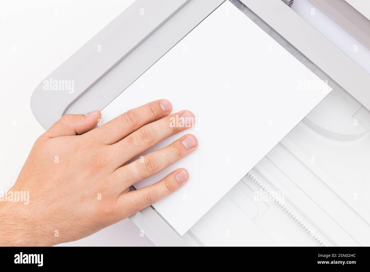 Hand placing blank paper onto a printer for scanning at an office desk ...