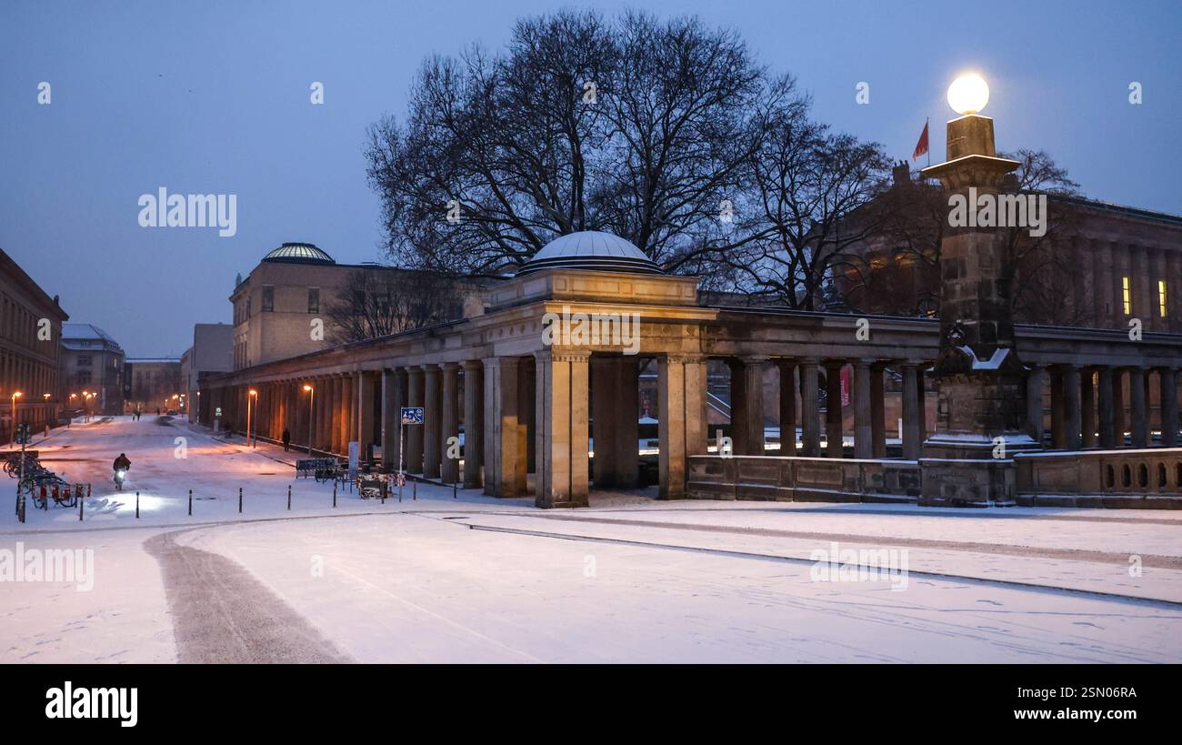 Winter in Berlin Ein Fahrradfahrer fährt am frühen Morgen über verschneite Straßen an der alten ...
