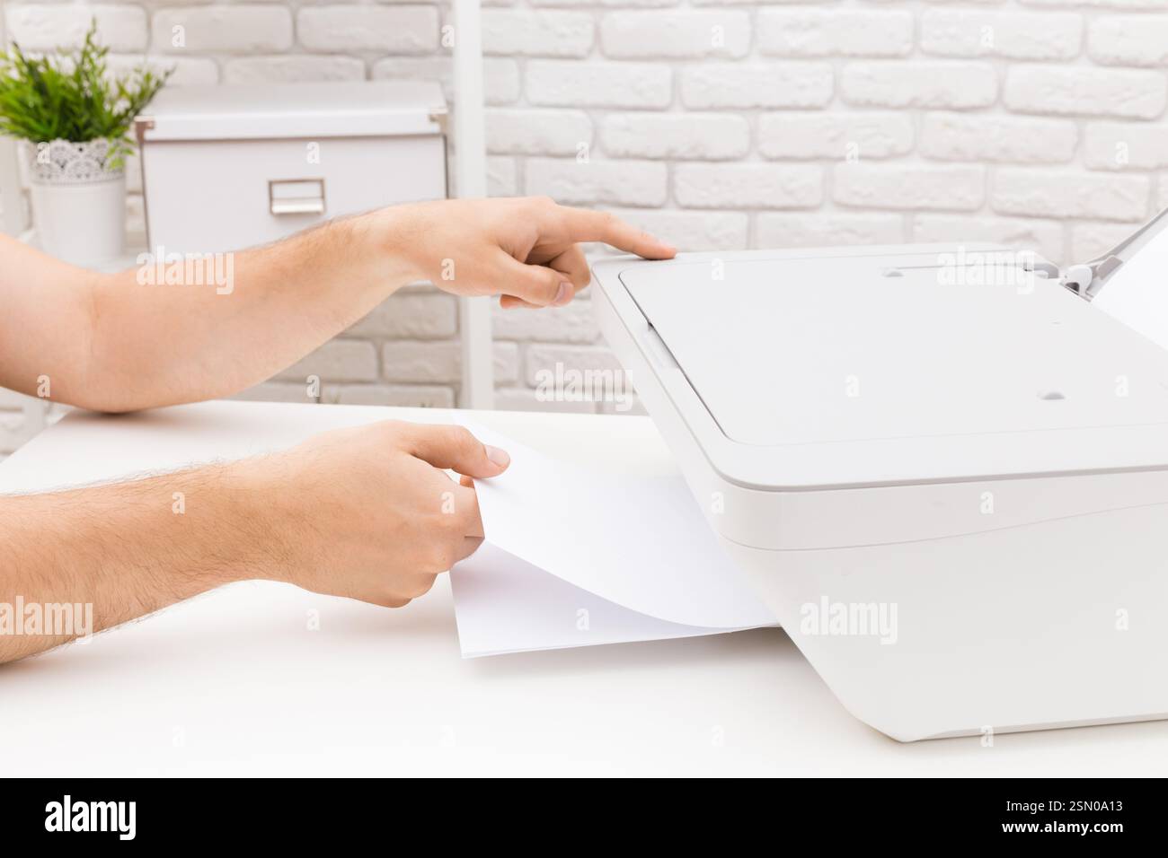 Manual paper handling at a home office setup includes printing tasks ...