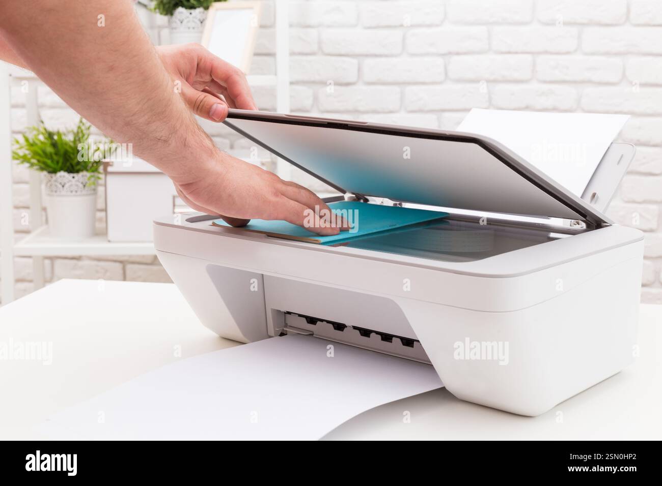 Hand placing documents into a printer in a bright and tidy office ...