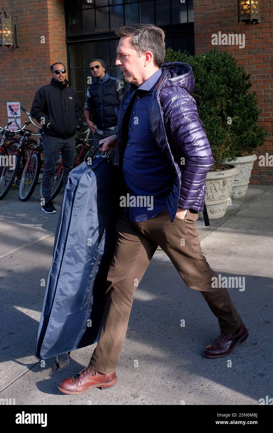 Actor Ed Helms carries a suit bag as he leaves a downtown hotel on ...