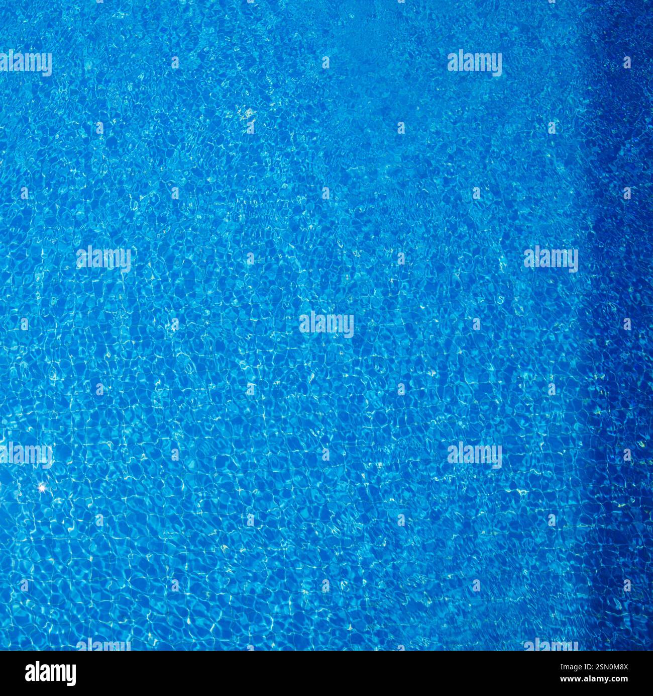Clear blue water reflecting sunlight in a tropical swimming pool during ...