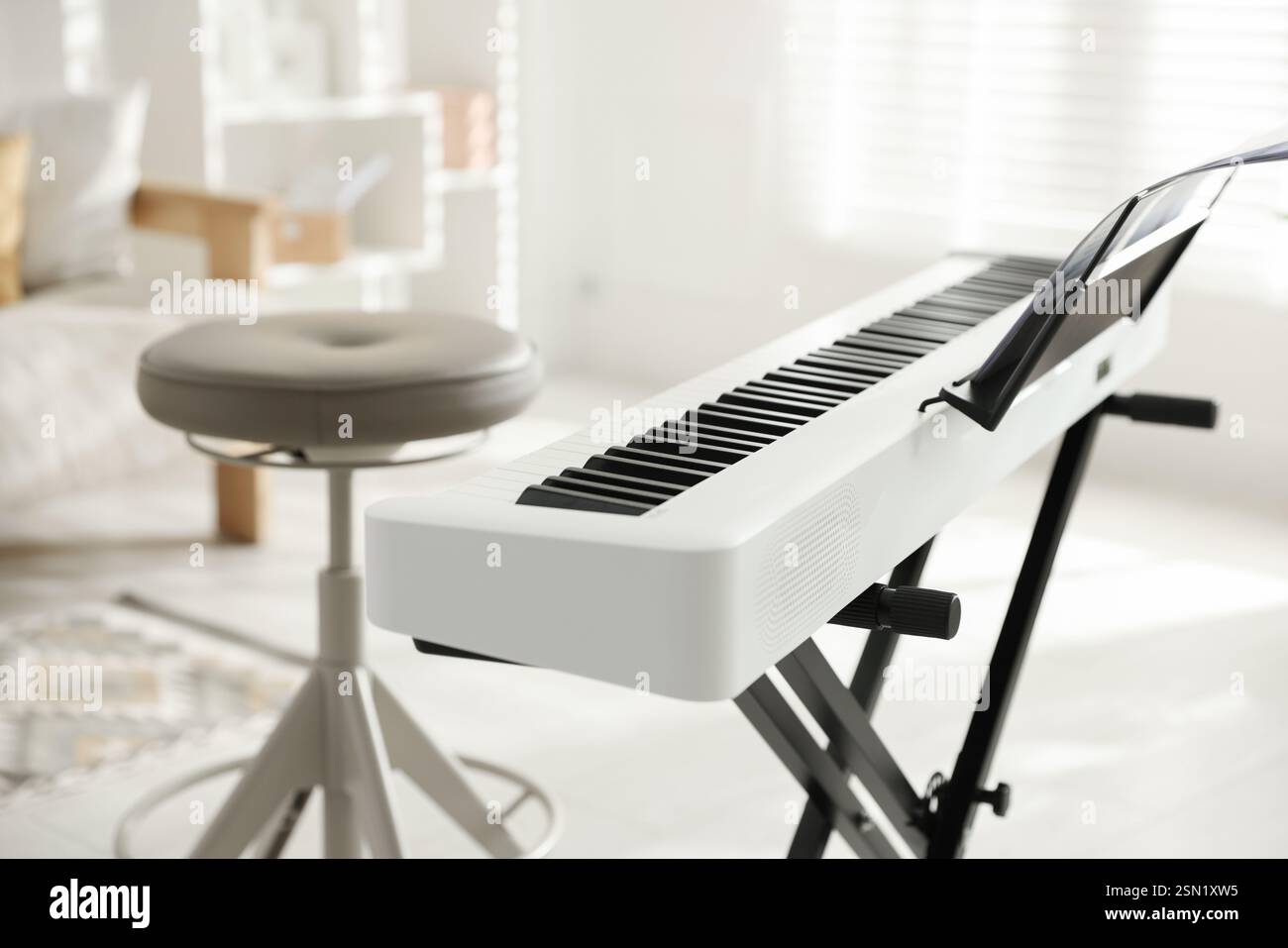Synthesizer with music sheets and chair indoors Stock Photo - Alamy