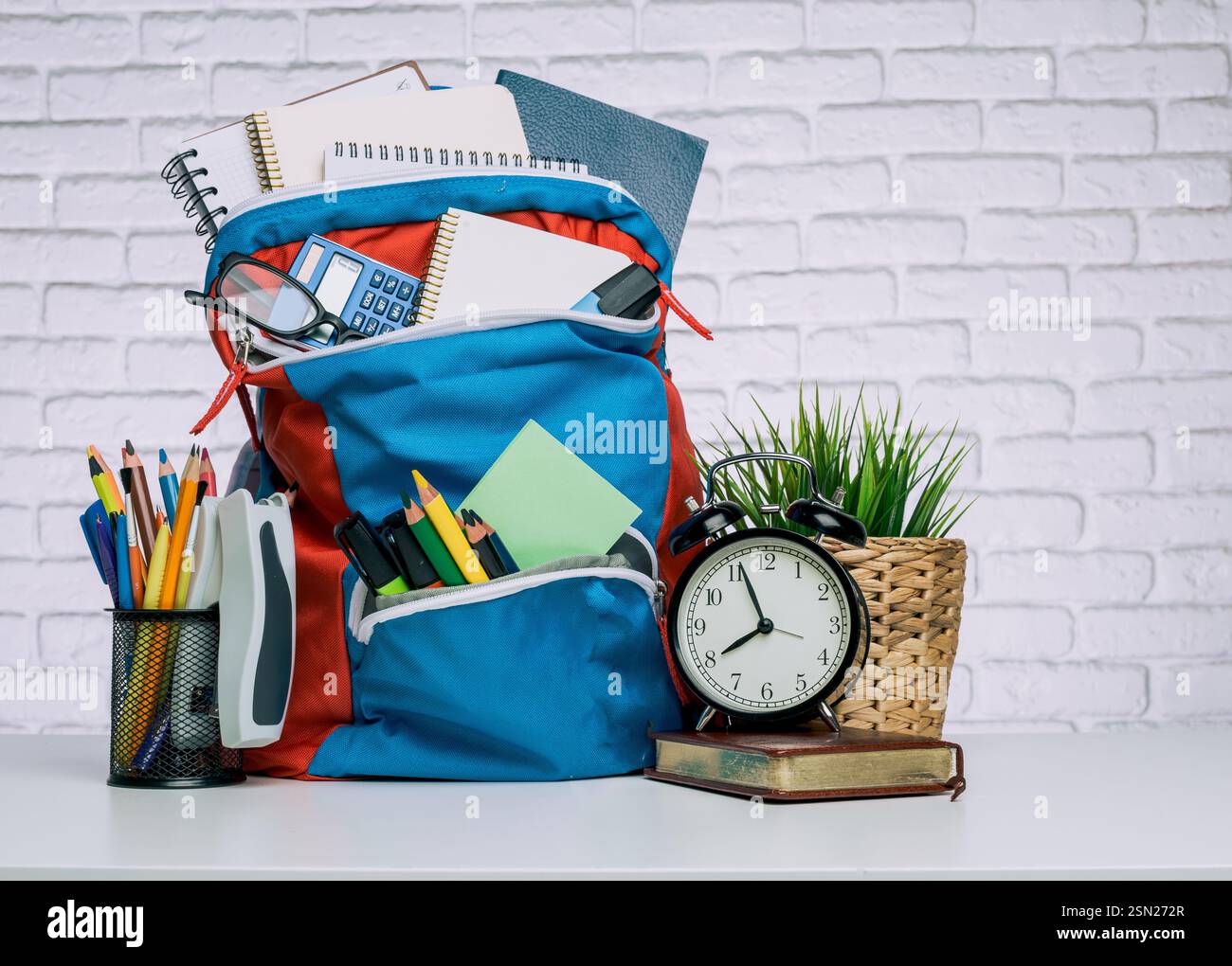Colorful backpack filled with school supplies on a desk in an organized ...
