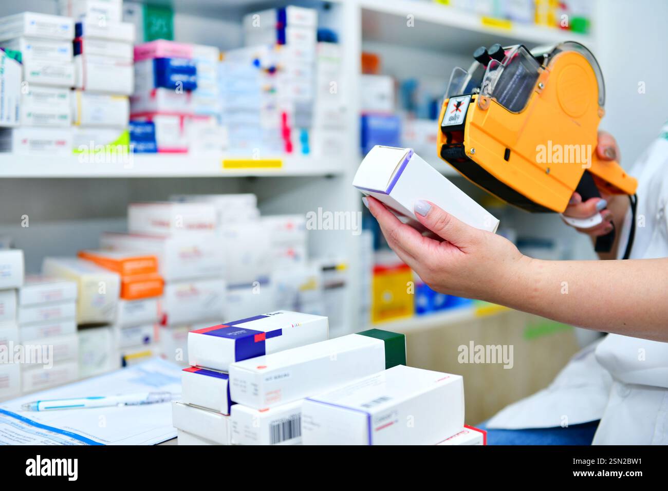 Hand of the pharmacist using yellow labeling gun for sticking price ...