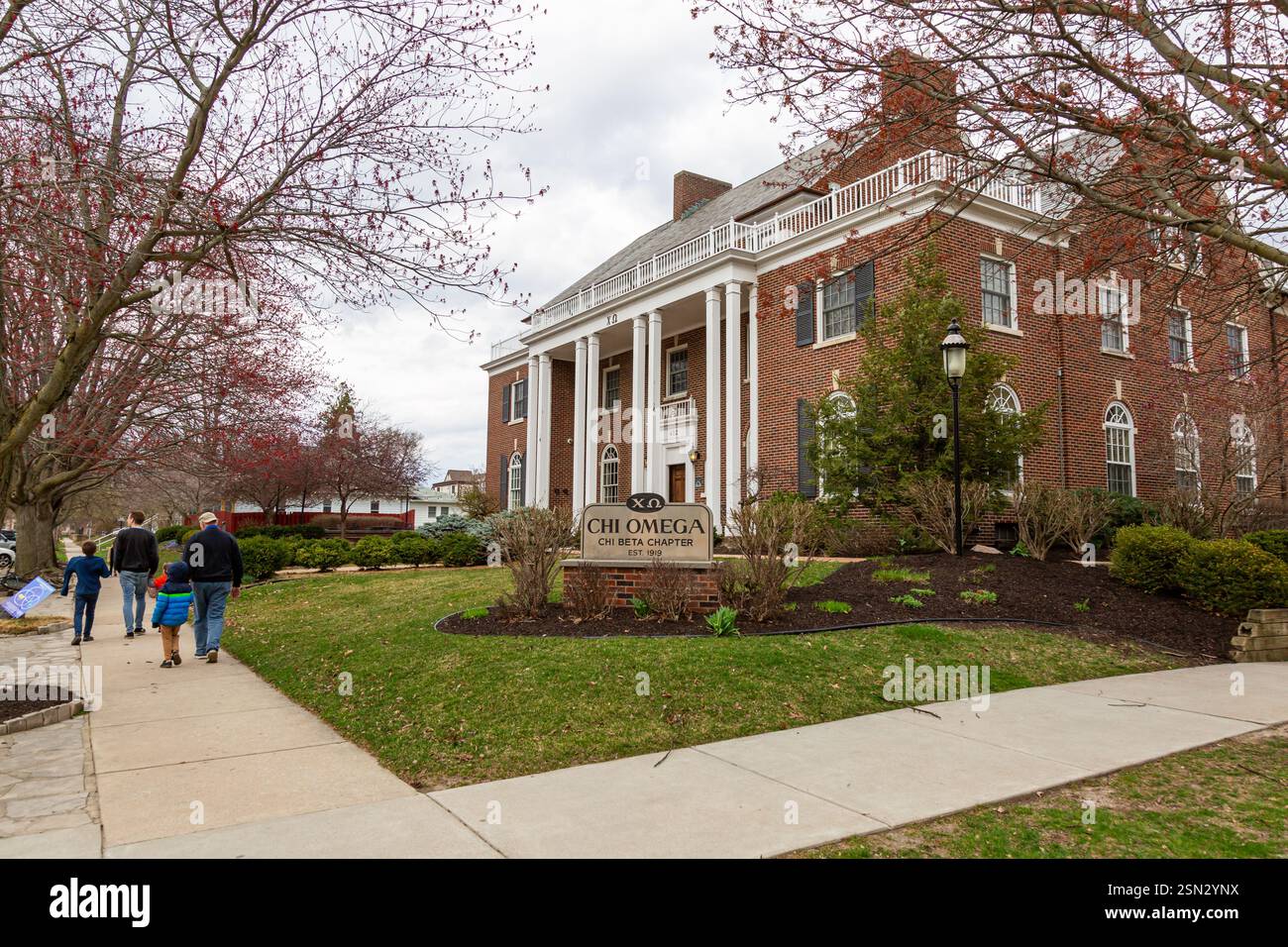A family walks past the Chi Omega sorority house on the campus of ...