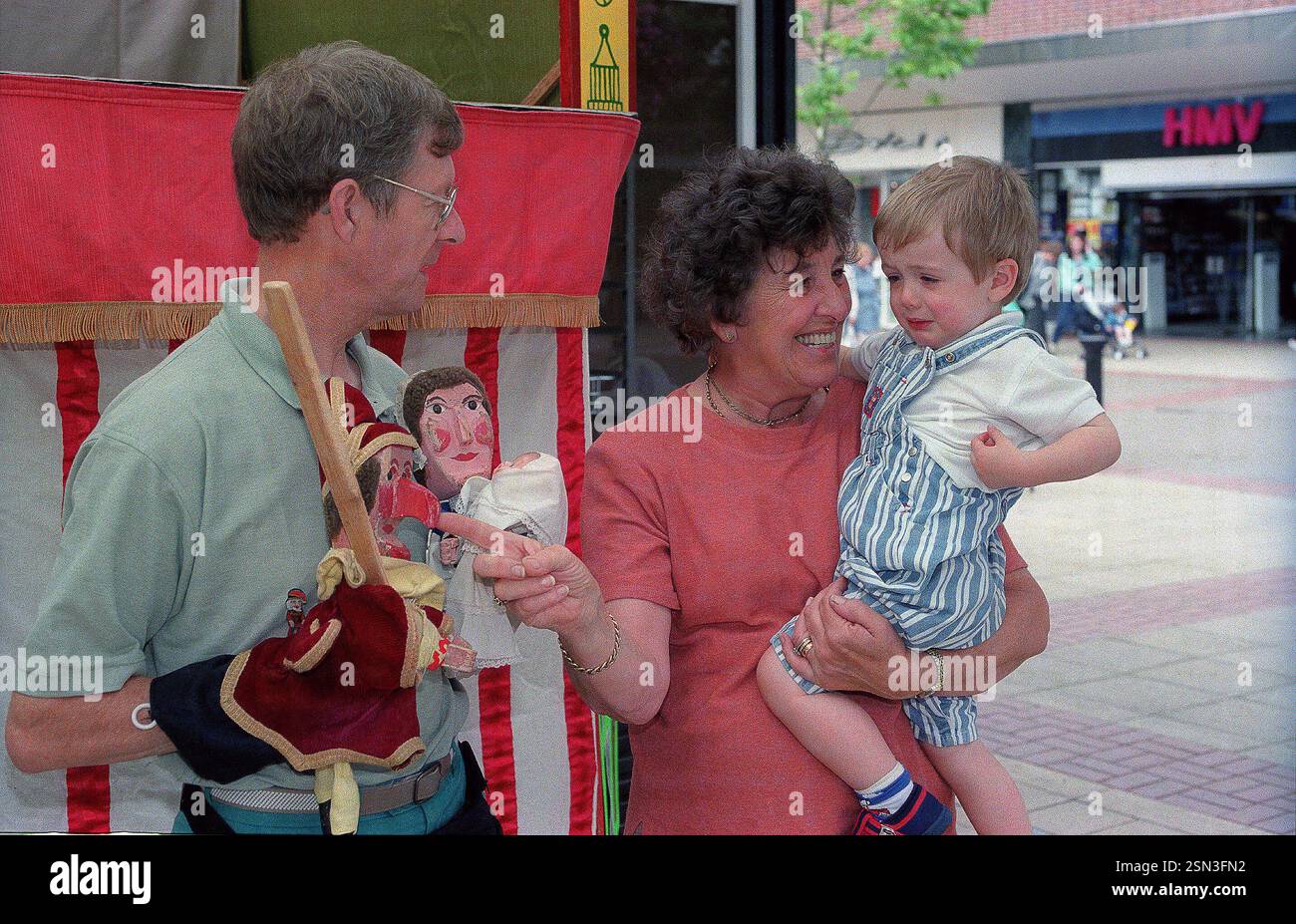 A young boy looks apprehensive when he meets Punch & Judy with their ...