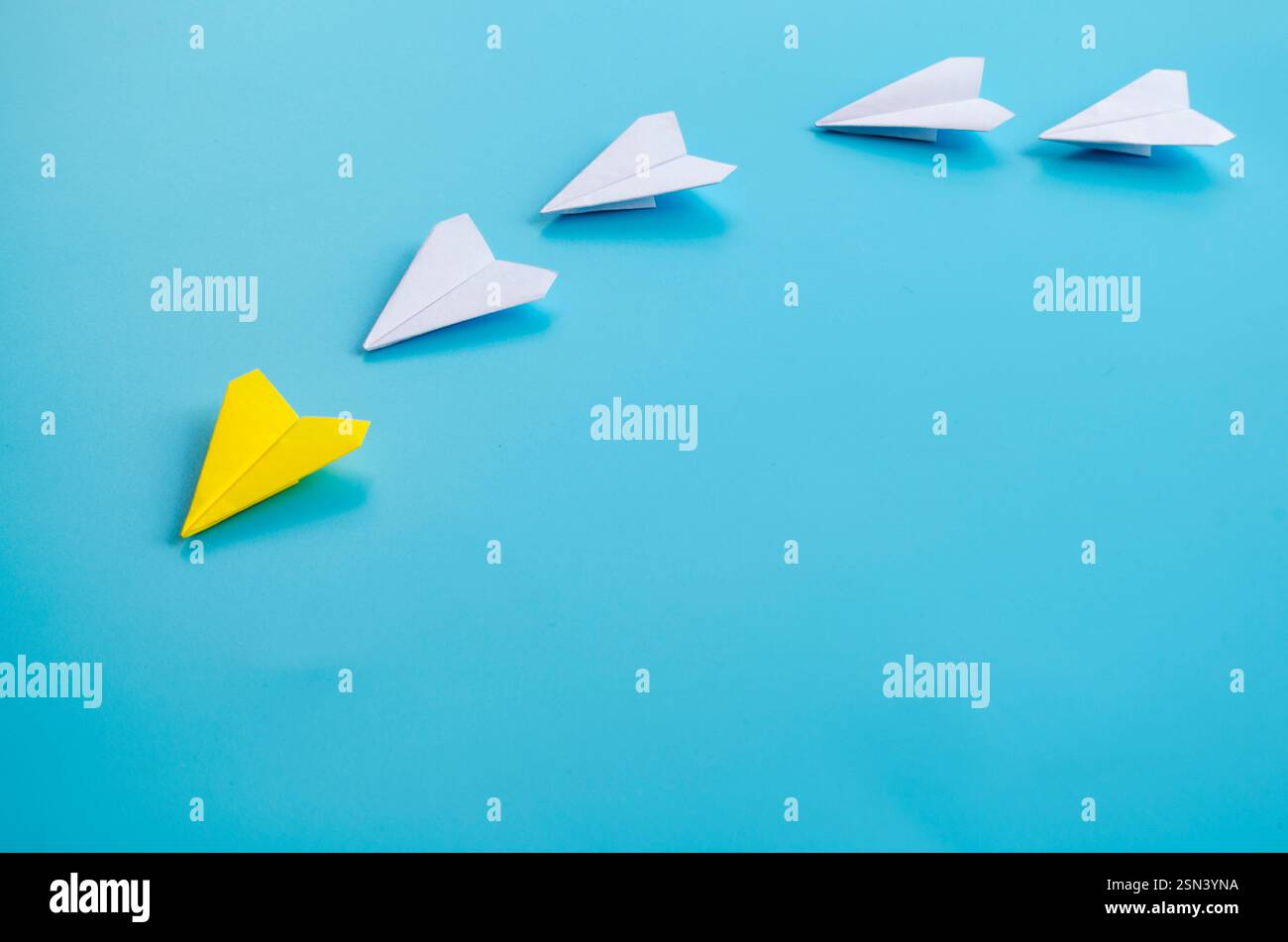 Side view of yellow paper airplane origami leading other white ...