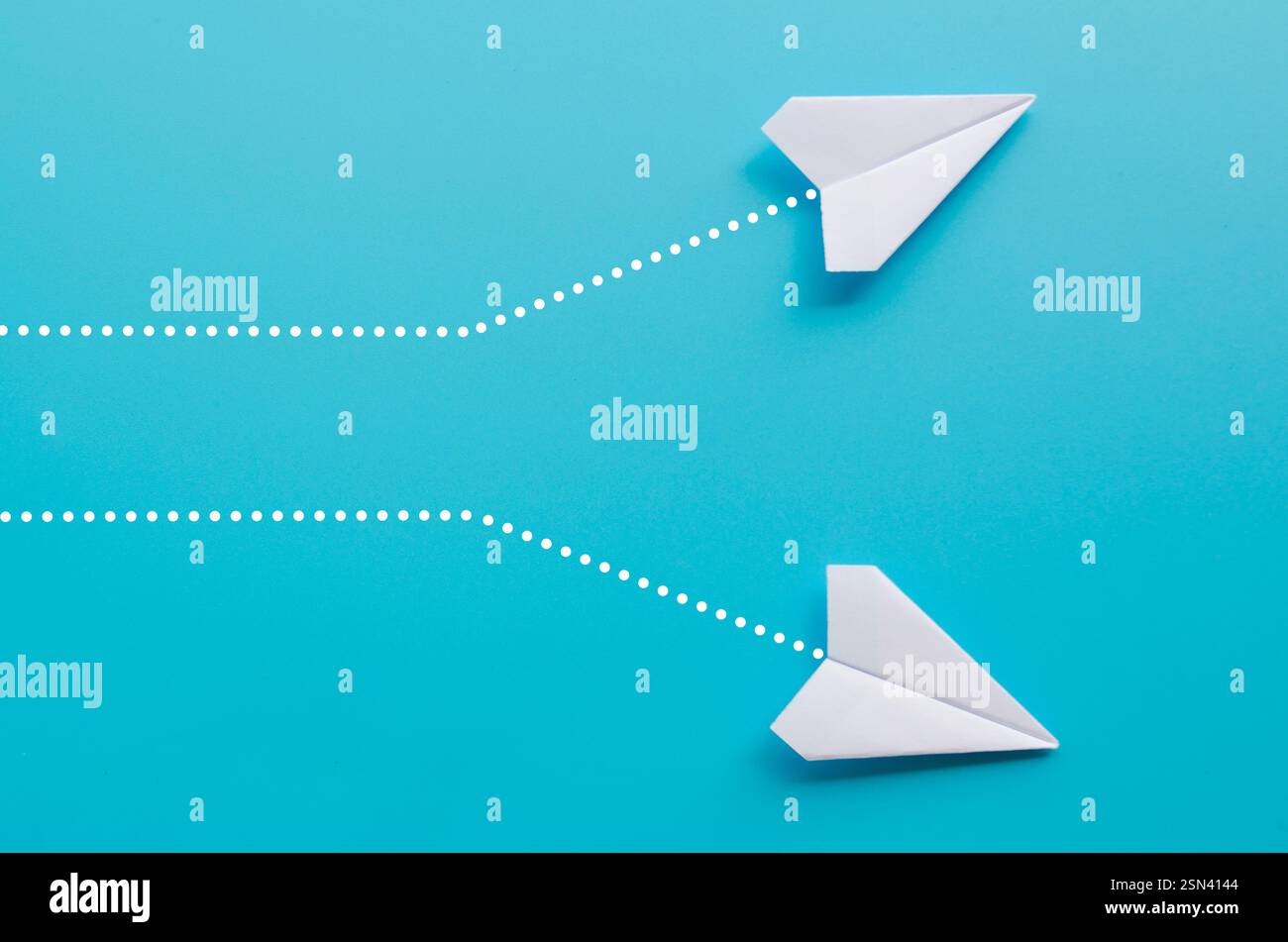 Top view of 2 white paper airplane heading to different direction on ...