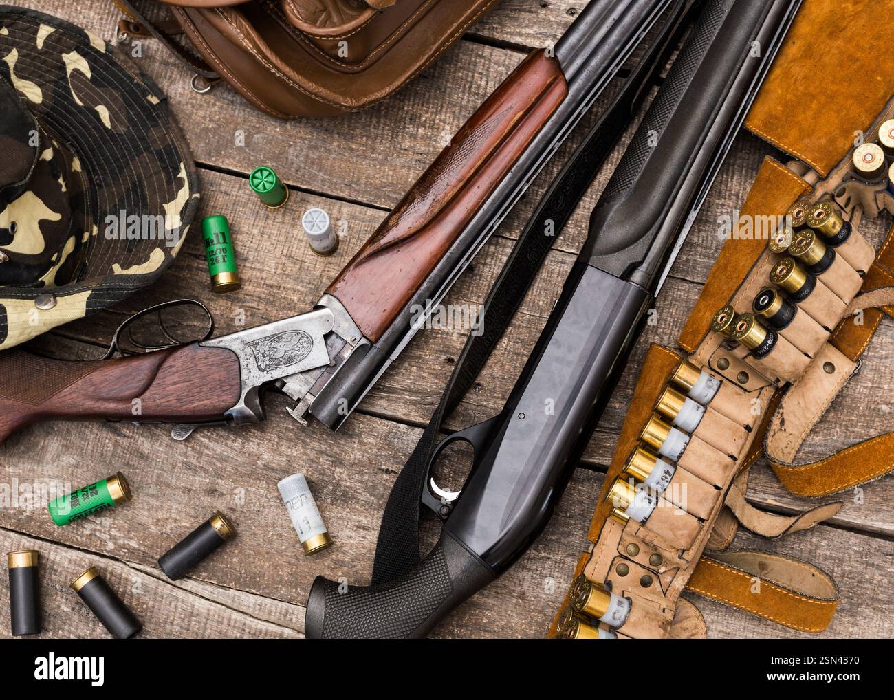 Collection of hunting firearms and accessories laid out on a rustic ...