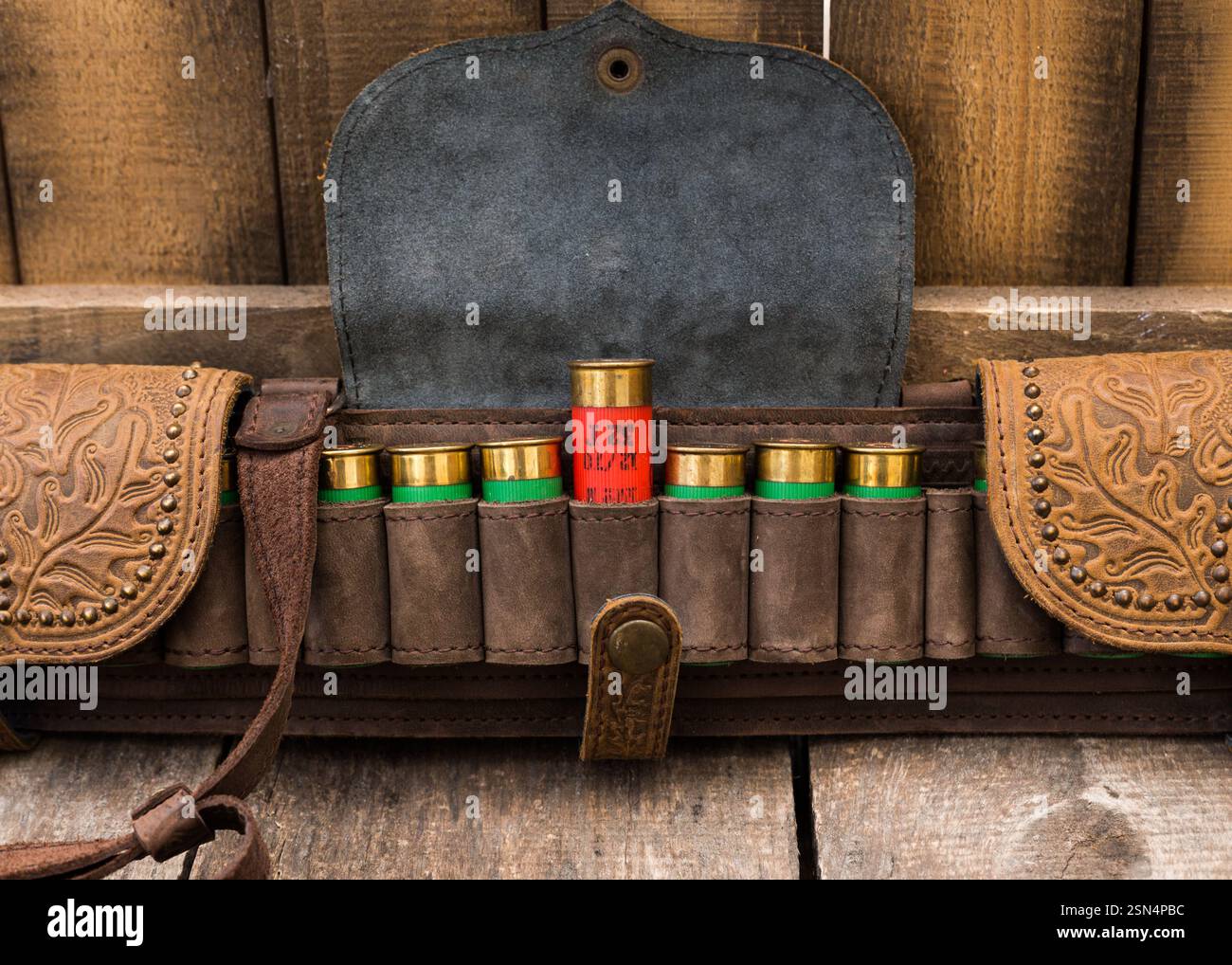 Leather shotgun shell holder displayed on wooden surface with shells ...