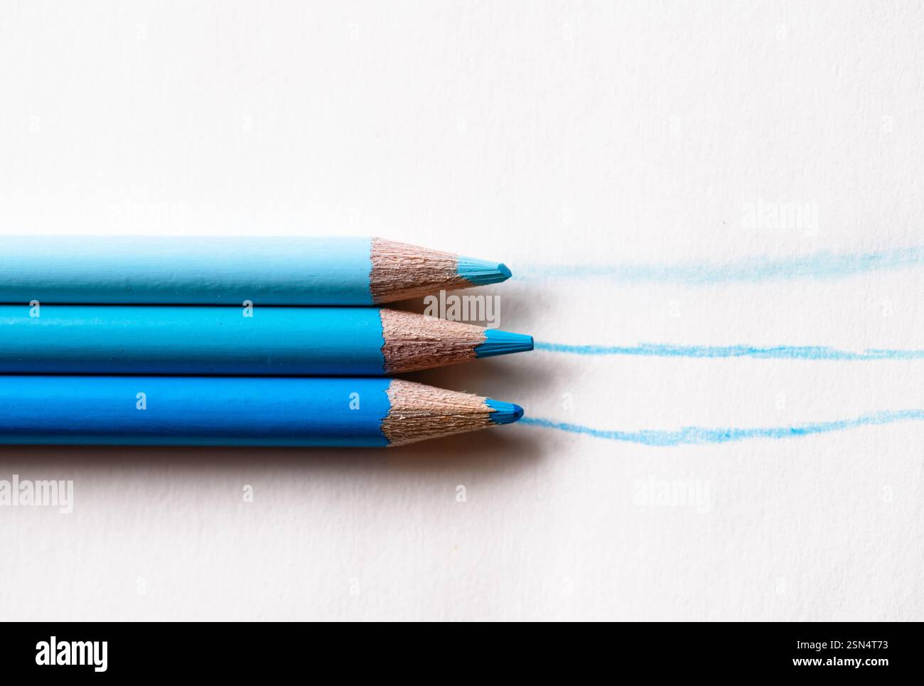 Three colored pencils in shades of blue with lines drawn on white ...