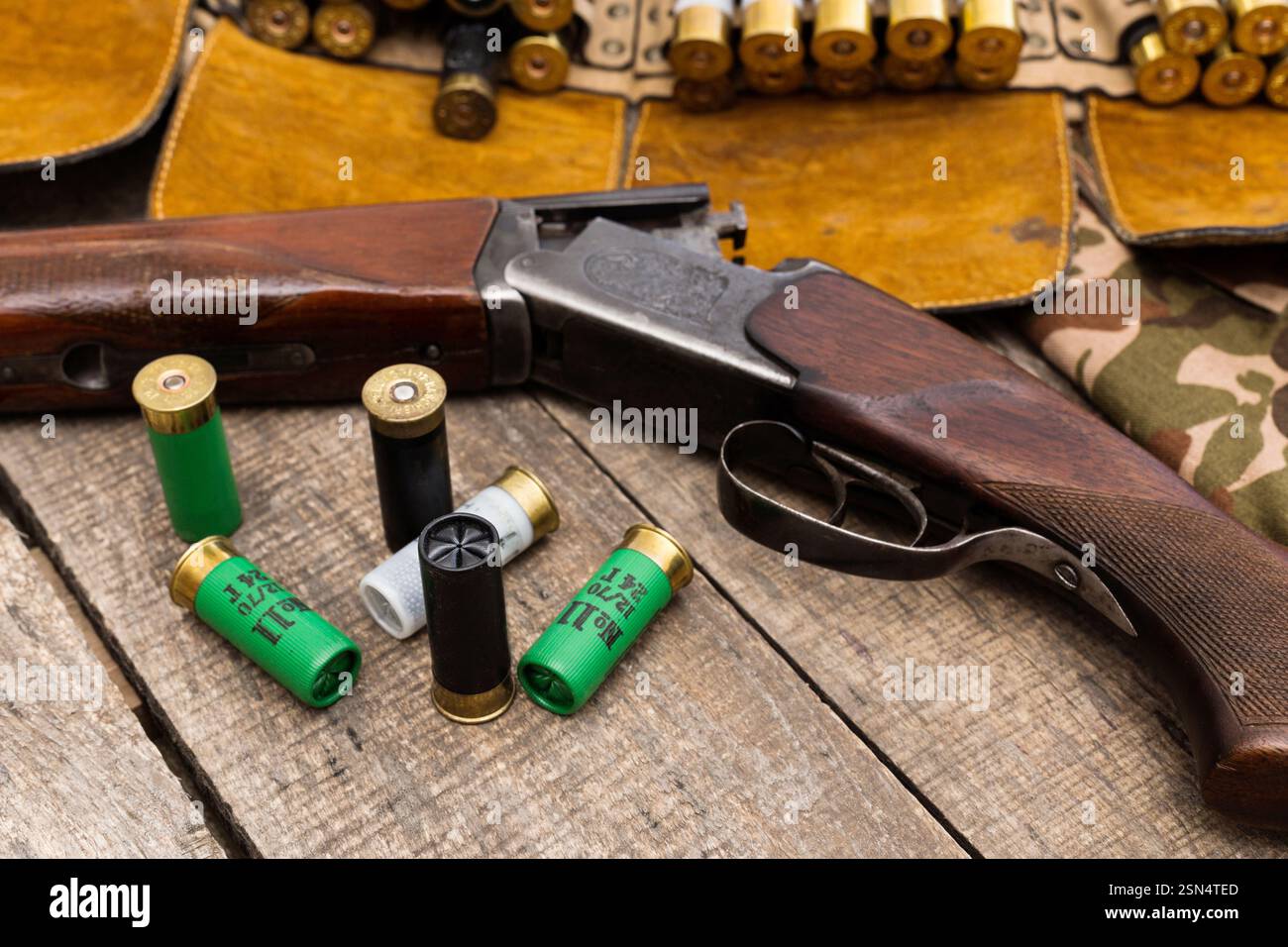 Vintage shotgun with ammunition and hunting gear arranged on a rustic ...