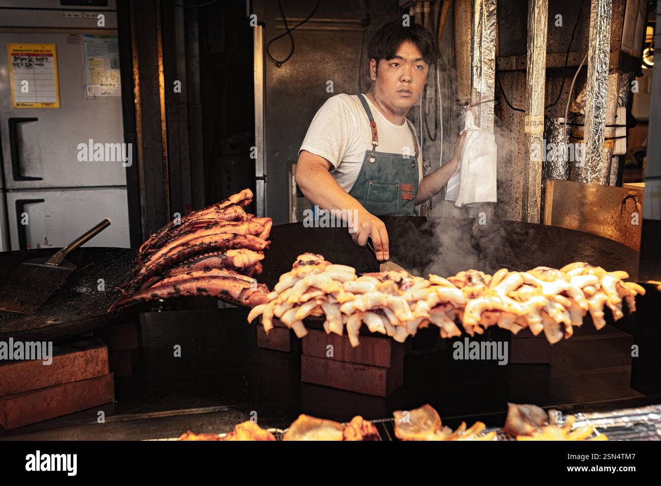 Korean man on the market cooking grill squid at Dongmun Traditional ...