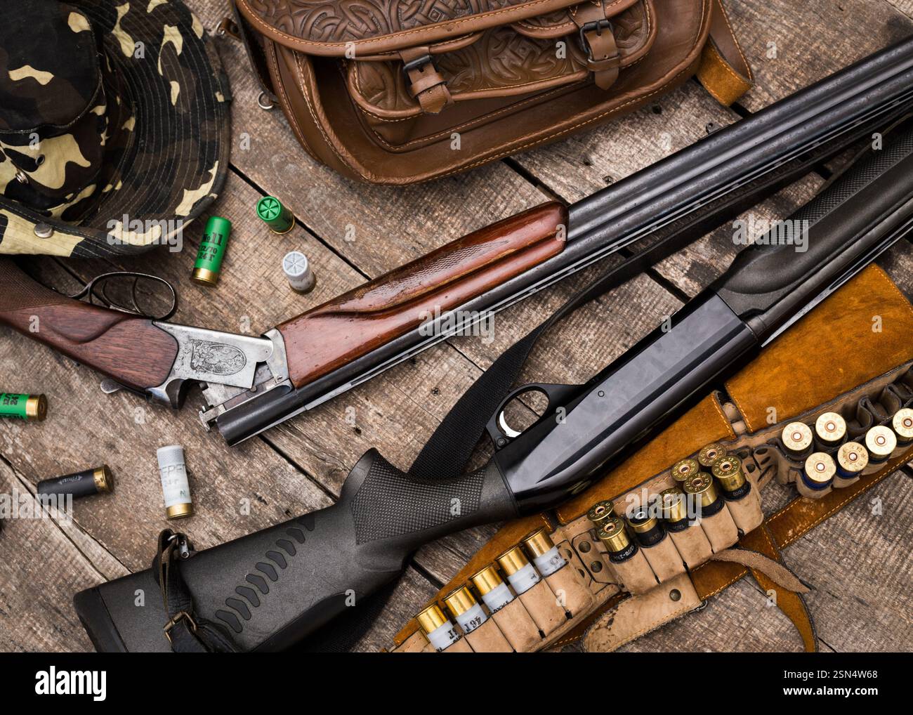Collection of hunting rifles and ammunition arranged on a rustic wooden ...