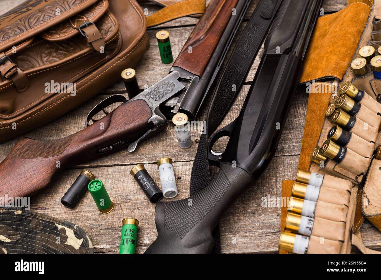 Collection of hunting firearms and ammunition displayed on wooden ...