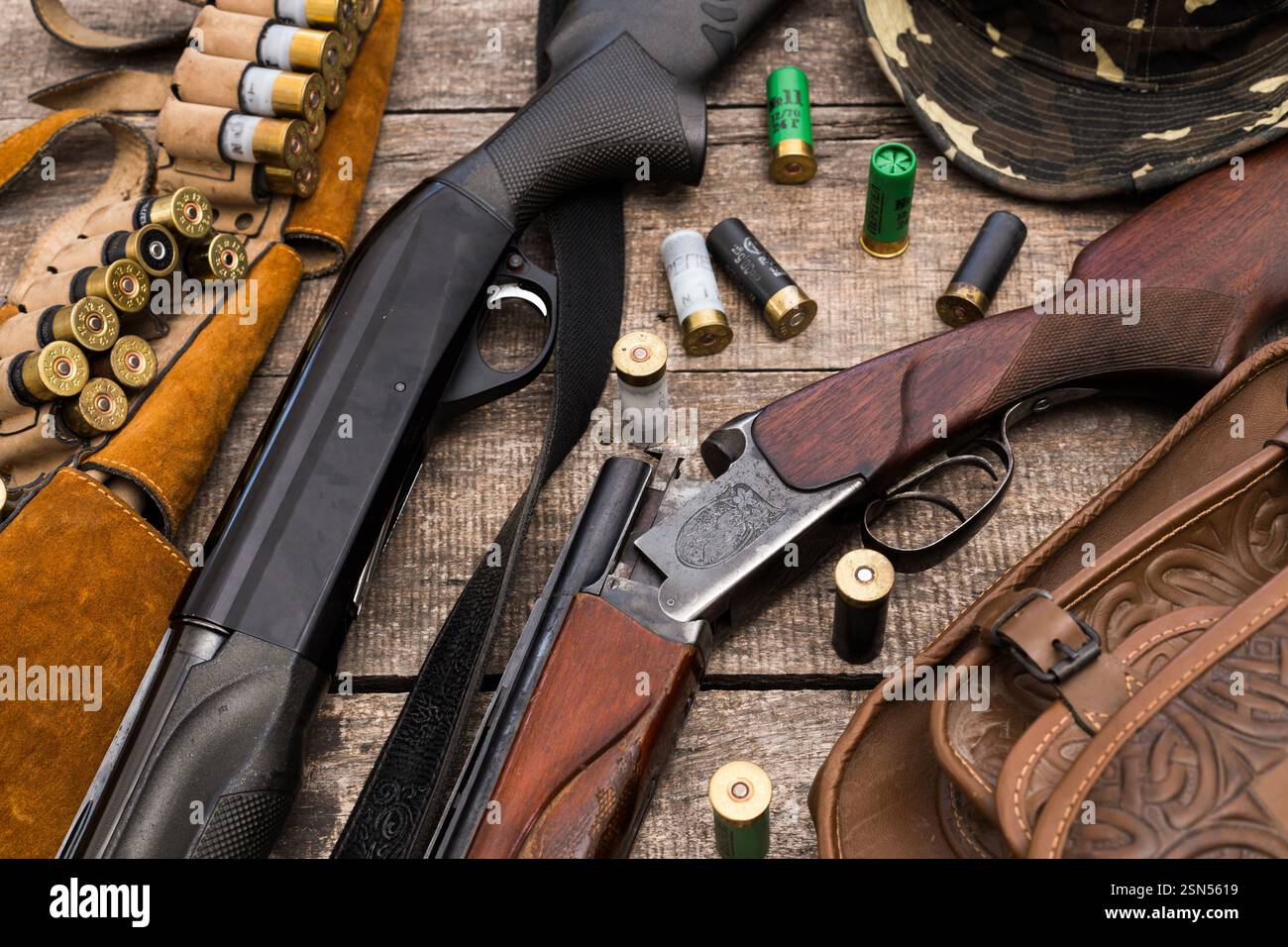 Collection of hunting firearms and ammunition displayed on a rustic ...