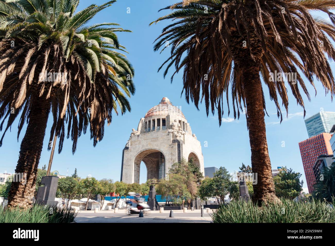 The Monument to the Revolution in Mexico City, framed by tall palm ...