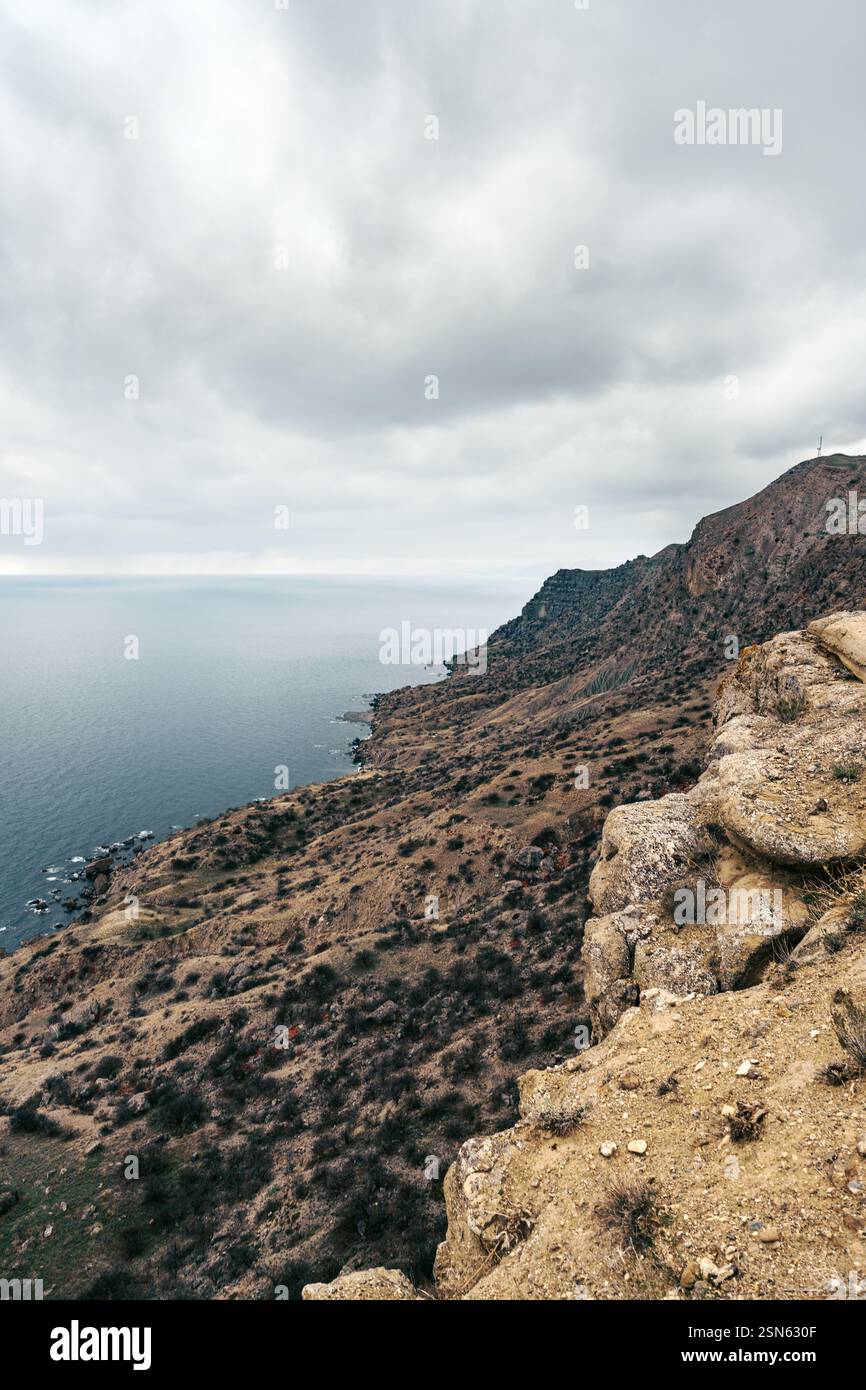 Coastal cliffs overlook a calm sea under a cloudy sky in a remote ...