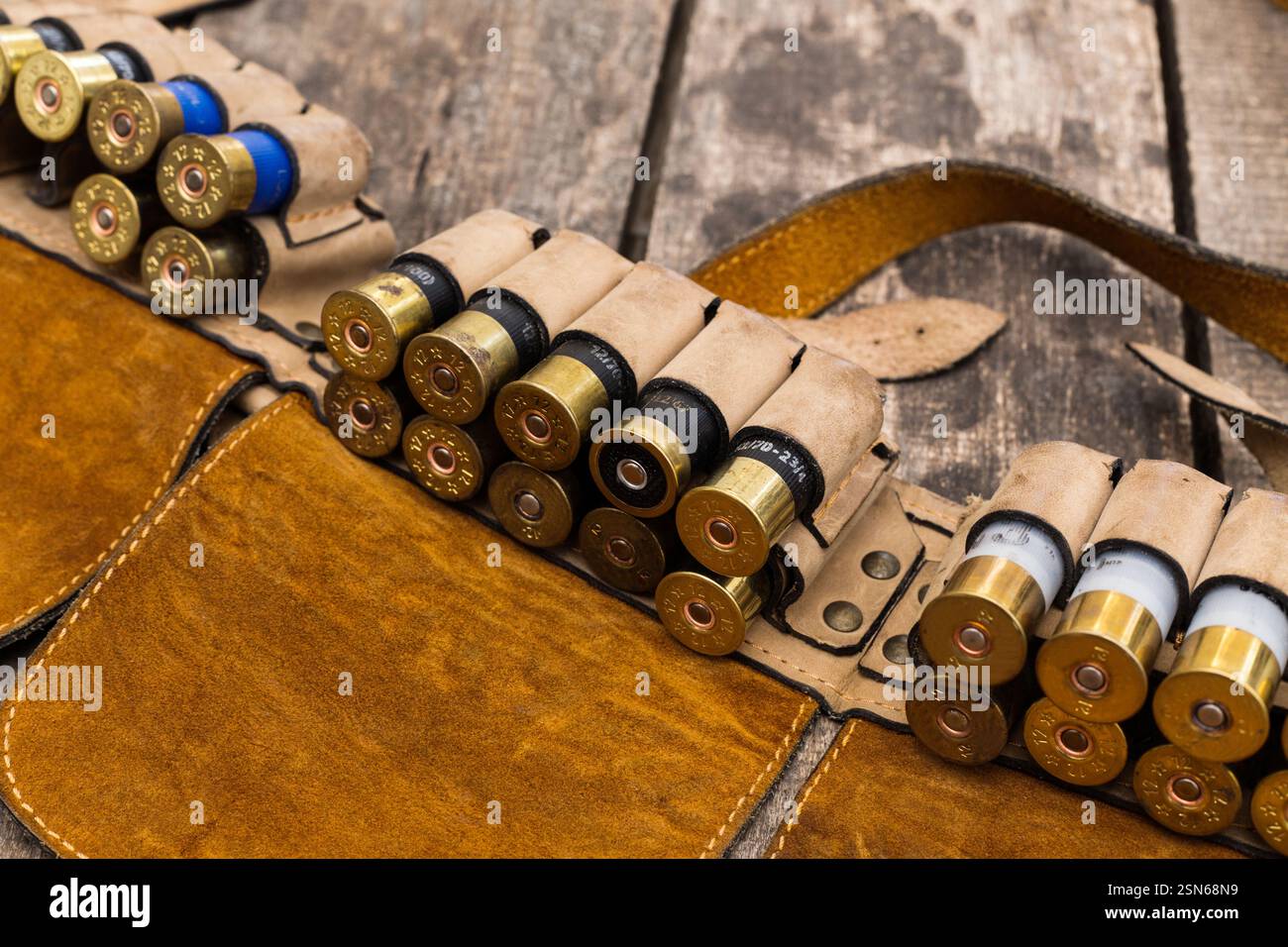 Shotgun shells arranged neatly in leather ammunition belt on rustic ...