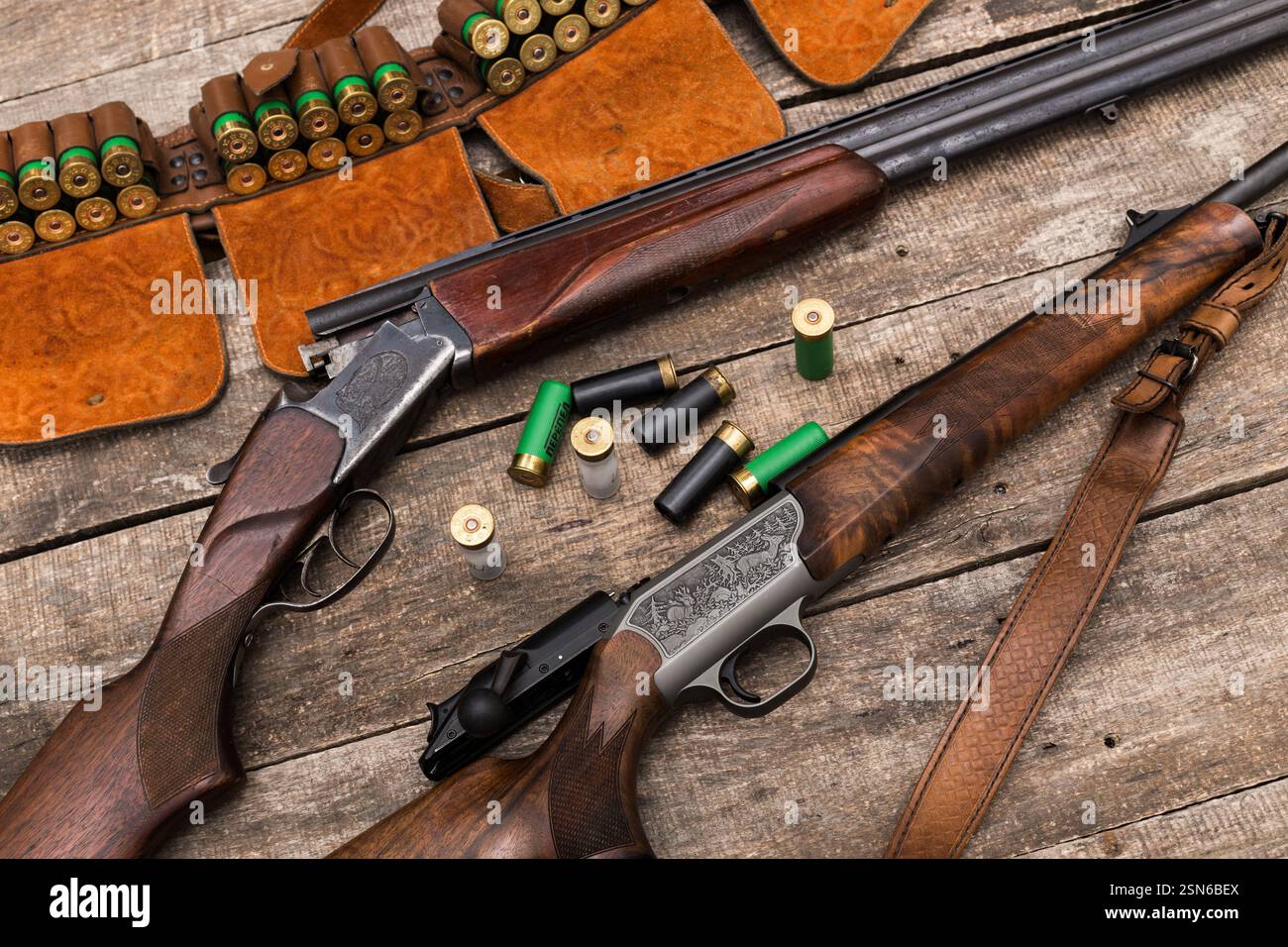 Collection of hunting shotguns and ammunition arranged on a rustic ...