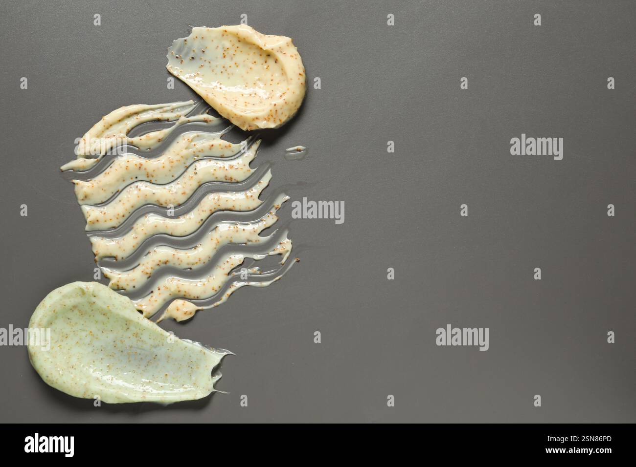 Samples of body scrubs on grey background, top view. Space for text ...