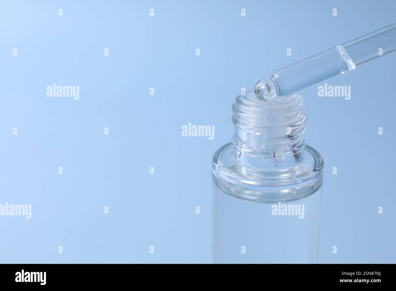 Dripping serum from pipette into bottle on light blue background ...