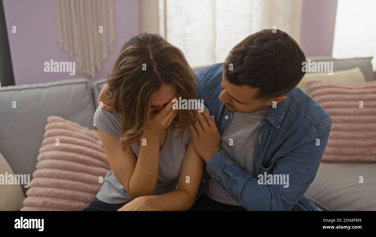 Woman crying while man comforts her on a couch in the living room of a ...