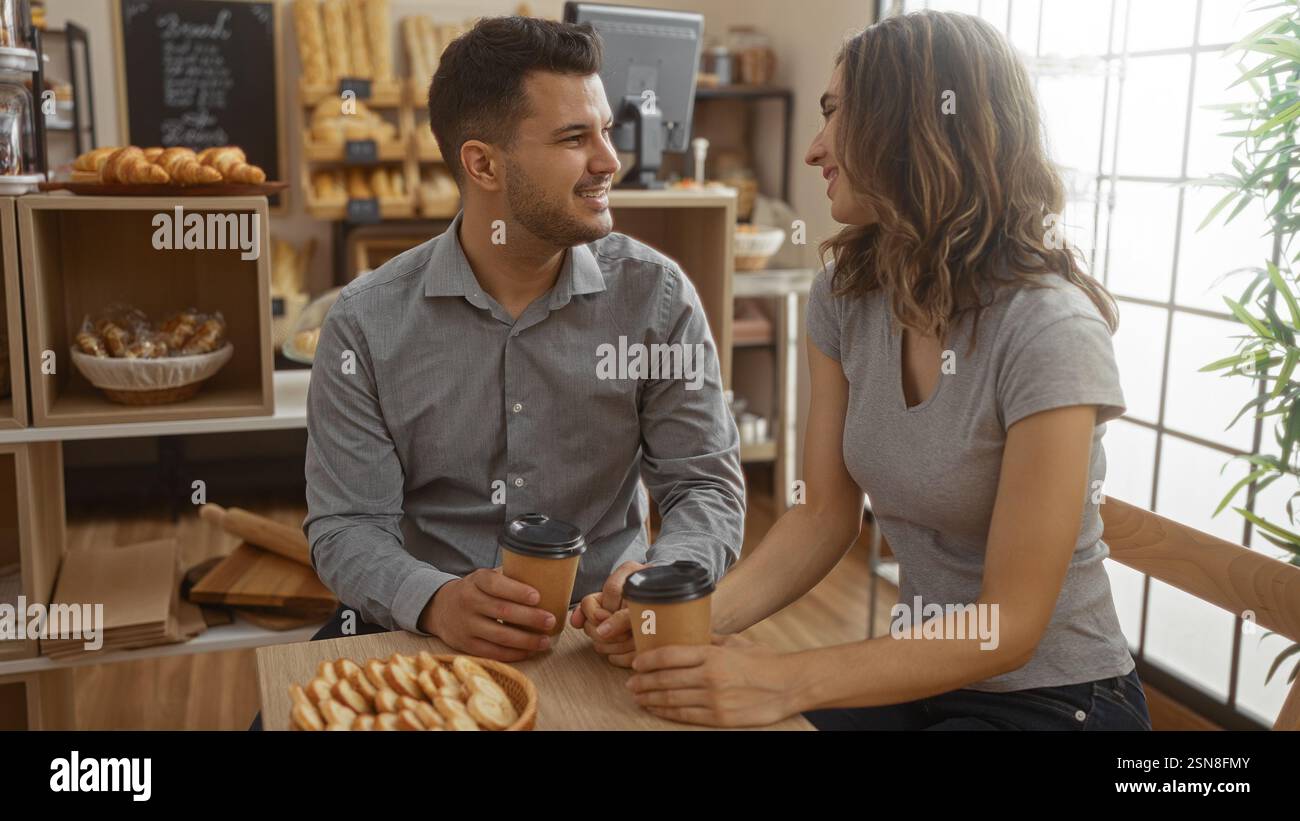Couple enjoying coffee together in bakery with croissants and pastries ...