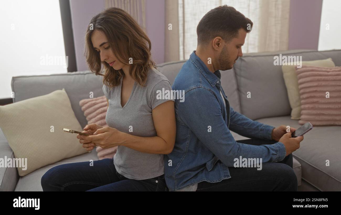 Couple sitting back-to-back using smartphones indoors depicting ...