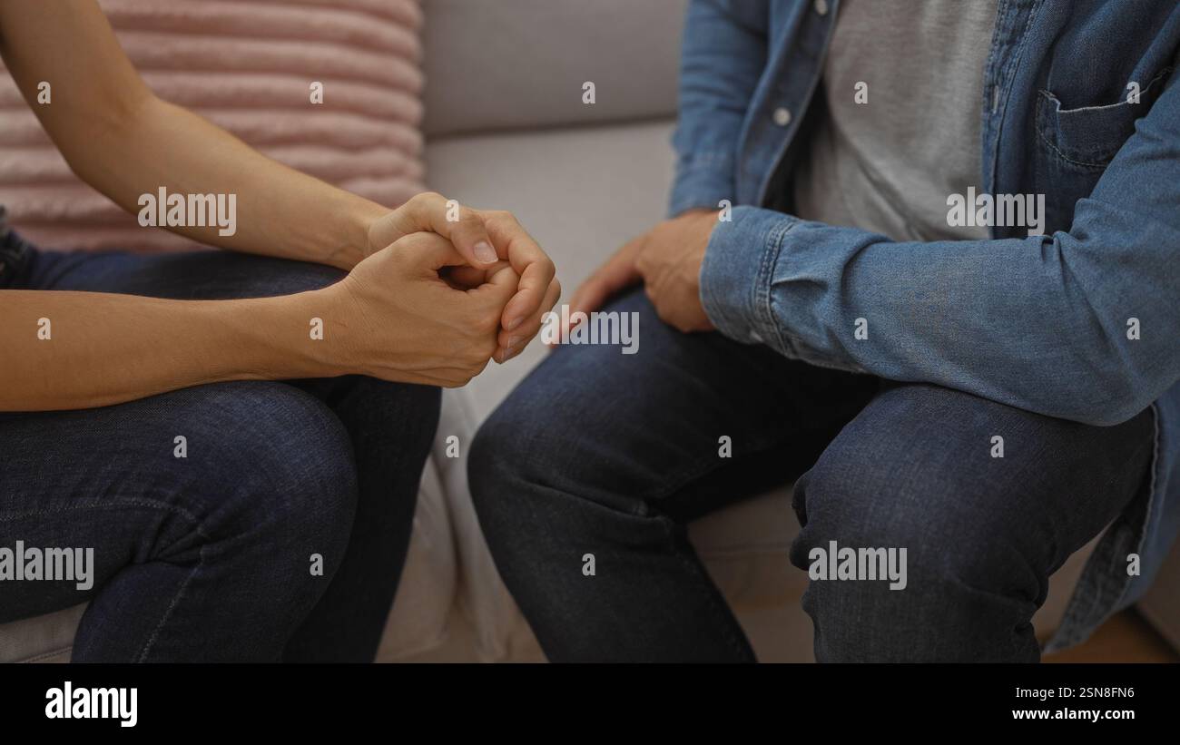 Couple sitting together indoors holding hands in a cozy living room ...