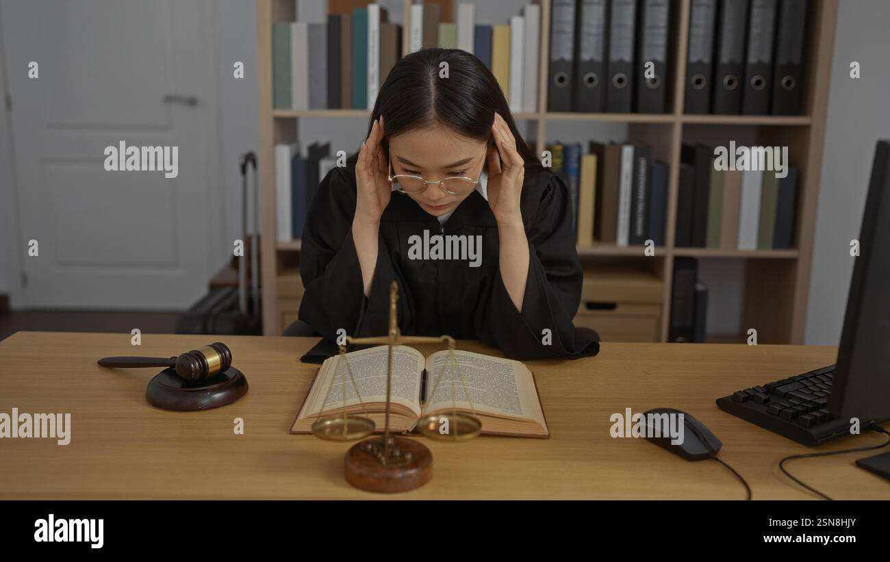Chinese female judge in office reading law book with scales and gavel ...
