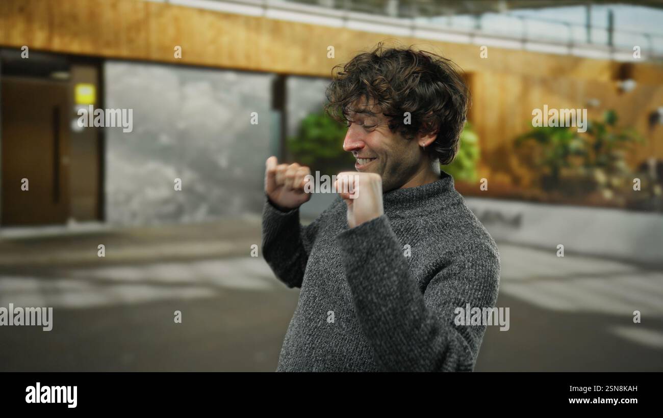 Young hispanic man dancing joyfully outdoors on a city street ...