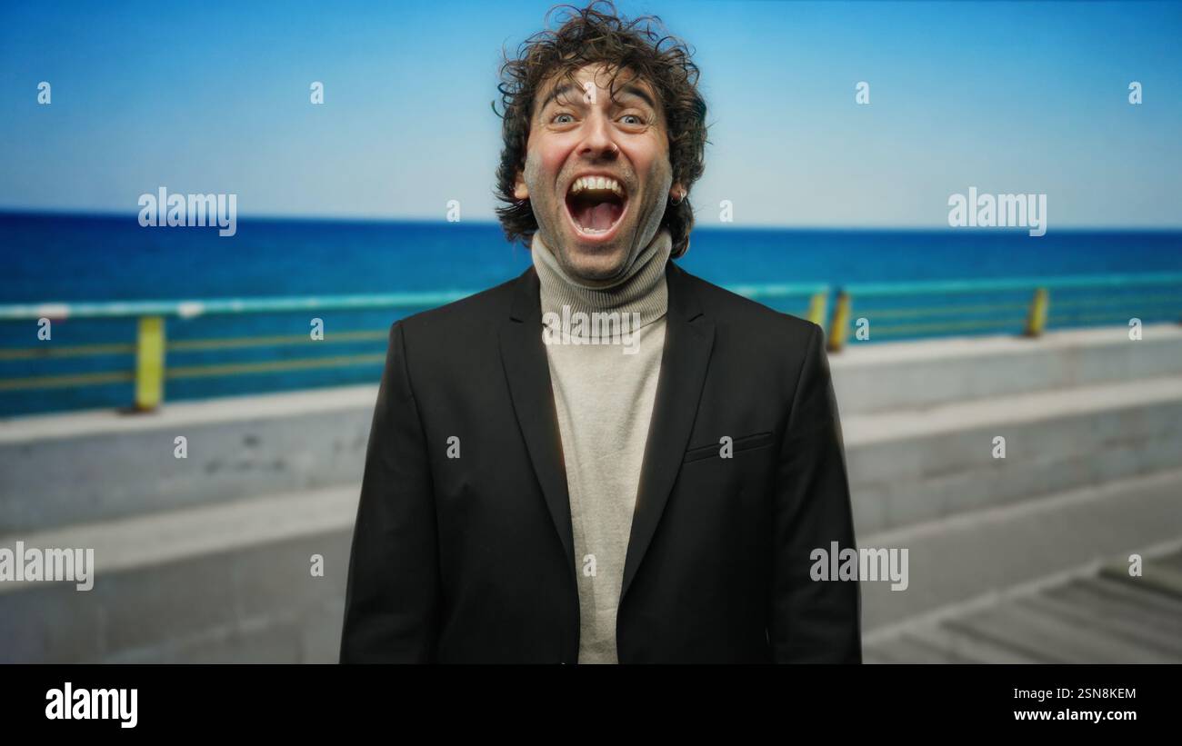Man smiling outdoors in a seaside setting, expressing joy in a casual ...