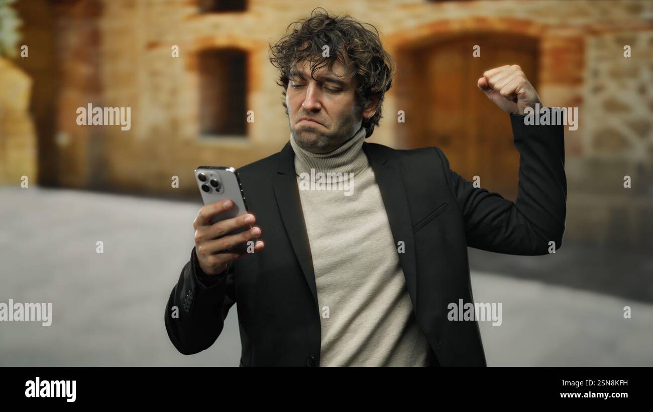 Man celebrating success on smartphone in urban street with expression ...