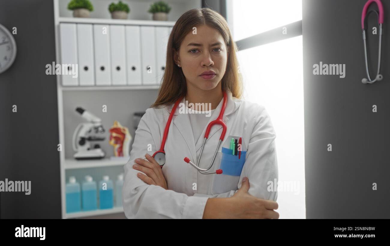 Confident woman doctor with stethoscope stands in a hospital room, arms ...