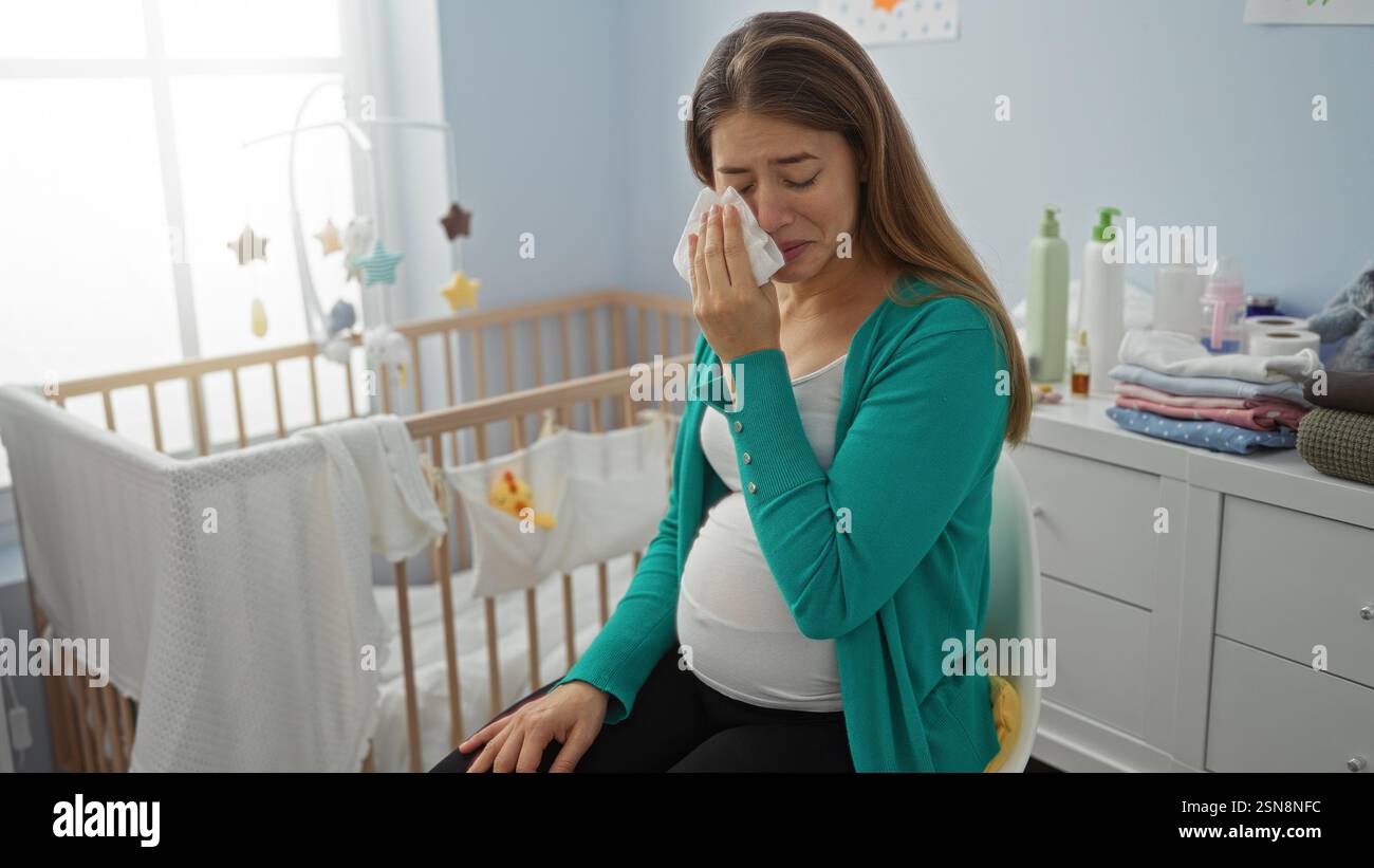 Woman sitting in bedroom with cradle wiping eyes, expressing emotions ...
