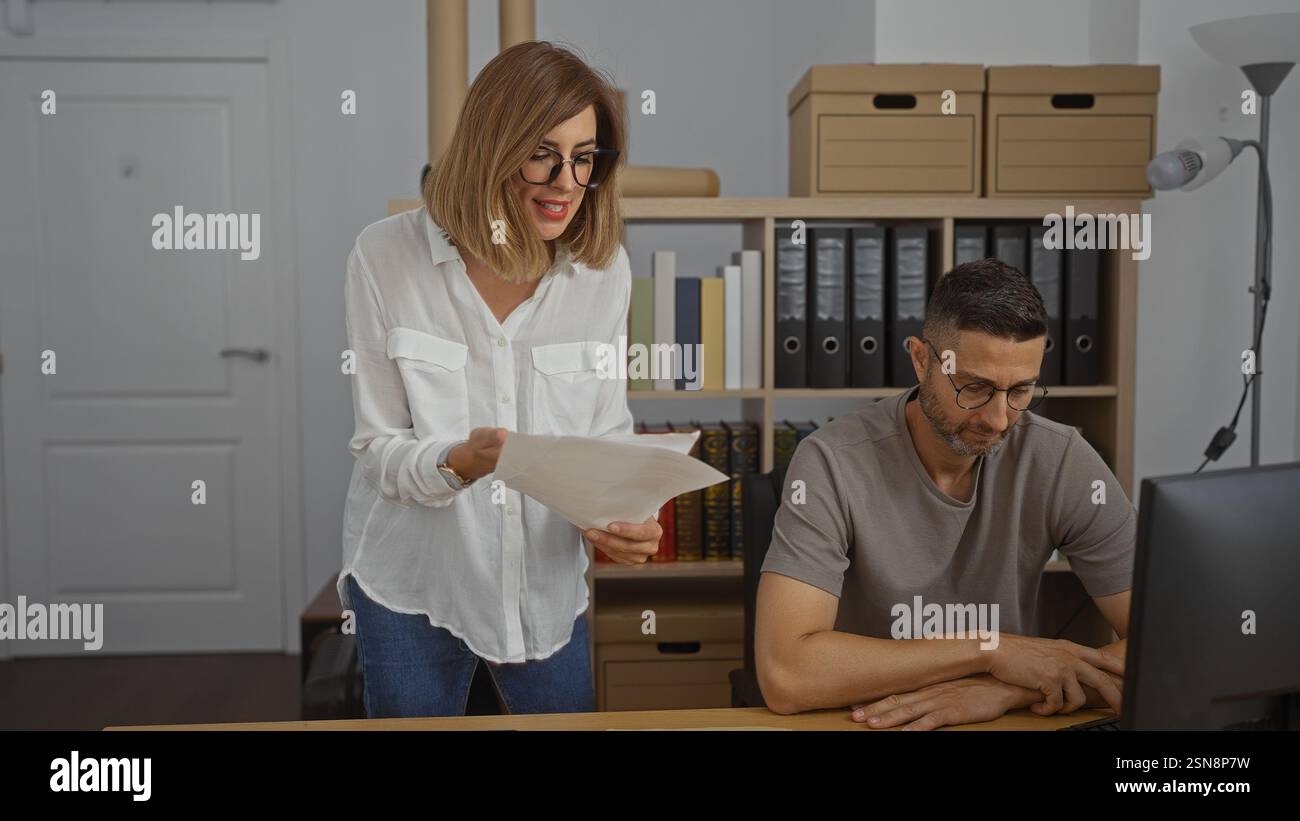 Woman presenting documents to man at office desk in a modern workplace ...