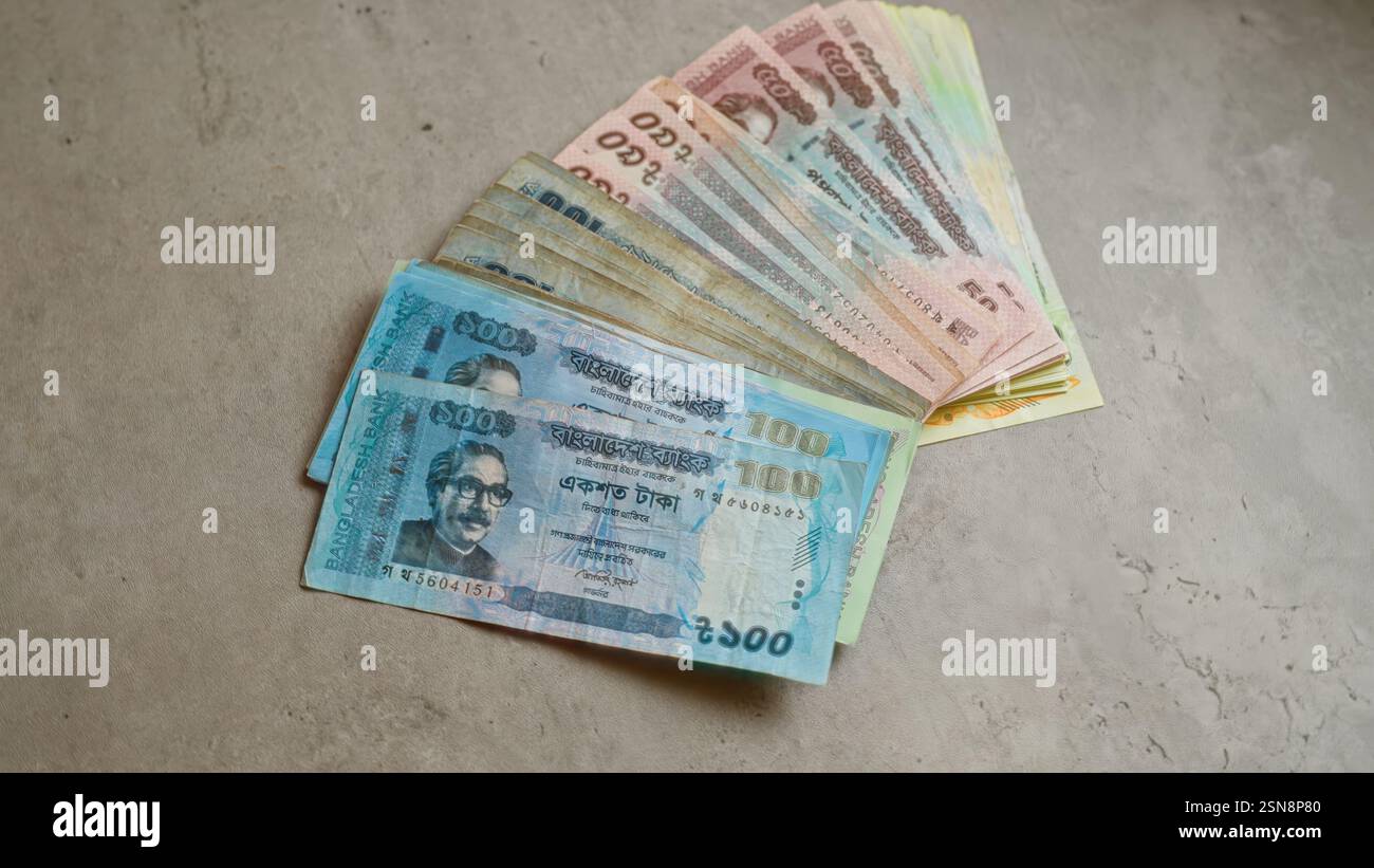 Bangladeshi banknotes, including taka, spread out on a rough concrete ...